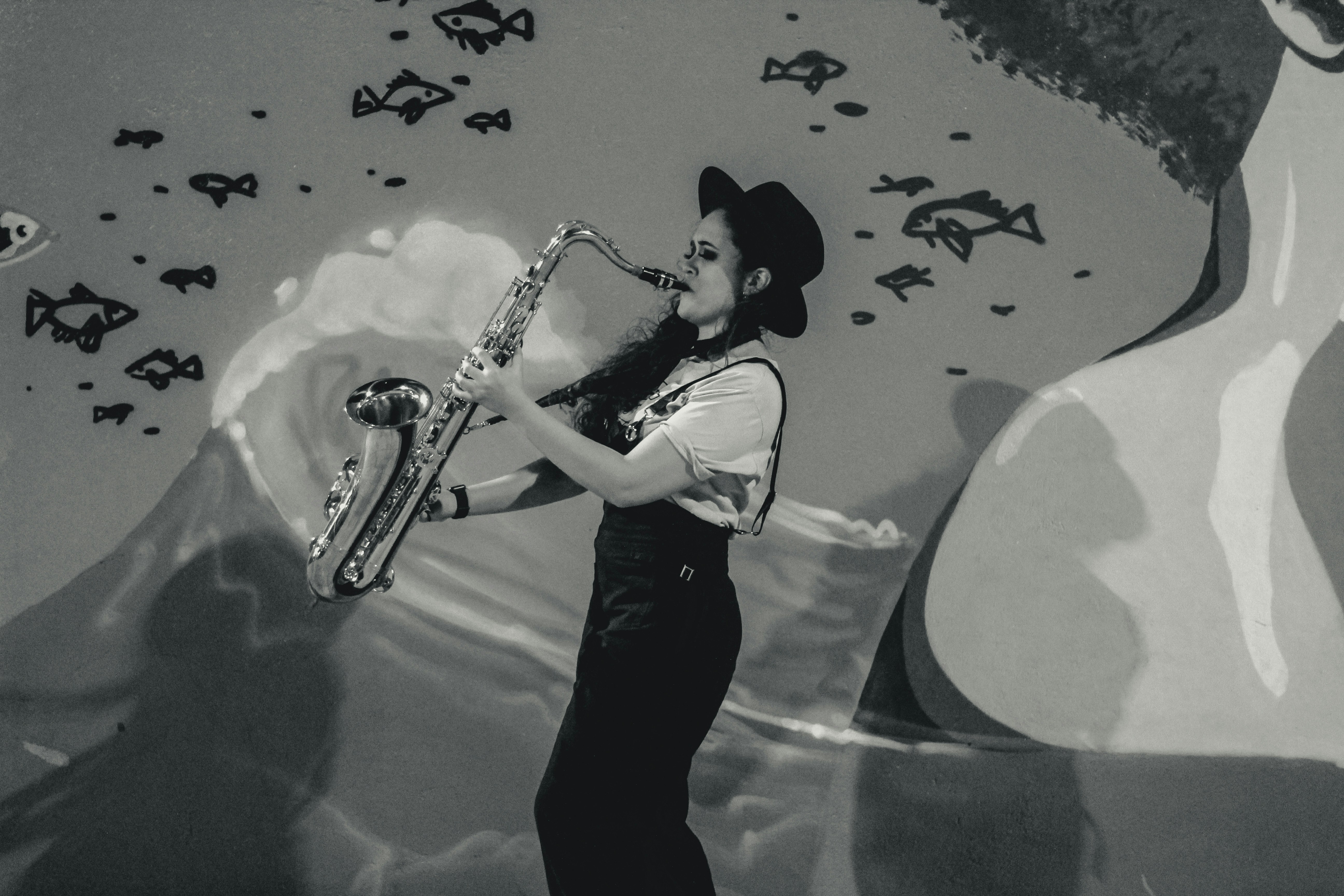 A man playing a saxophone in front of a painting photo – Free Human ...