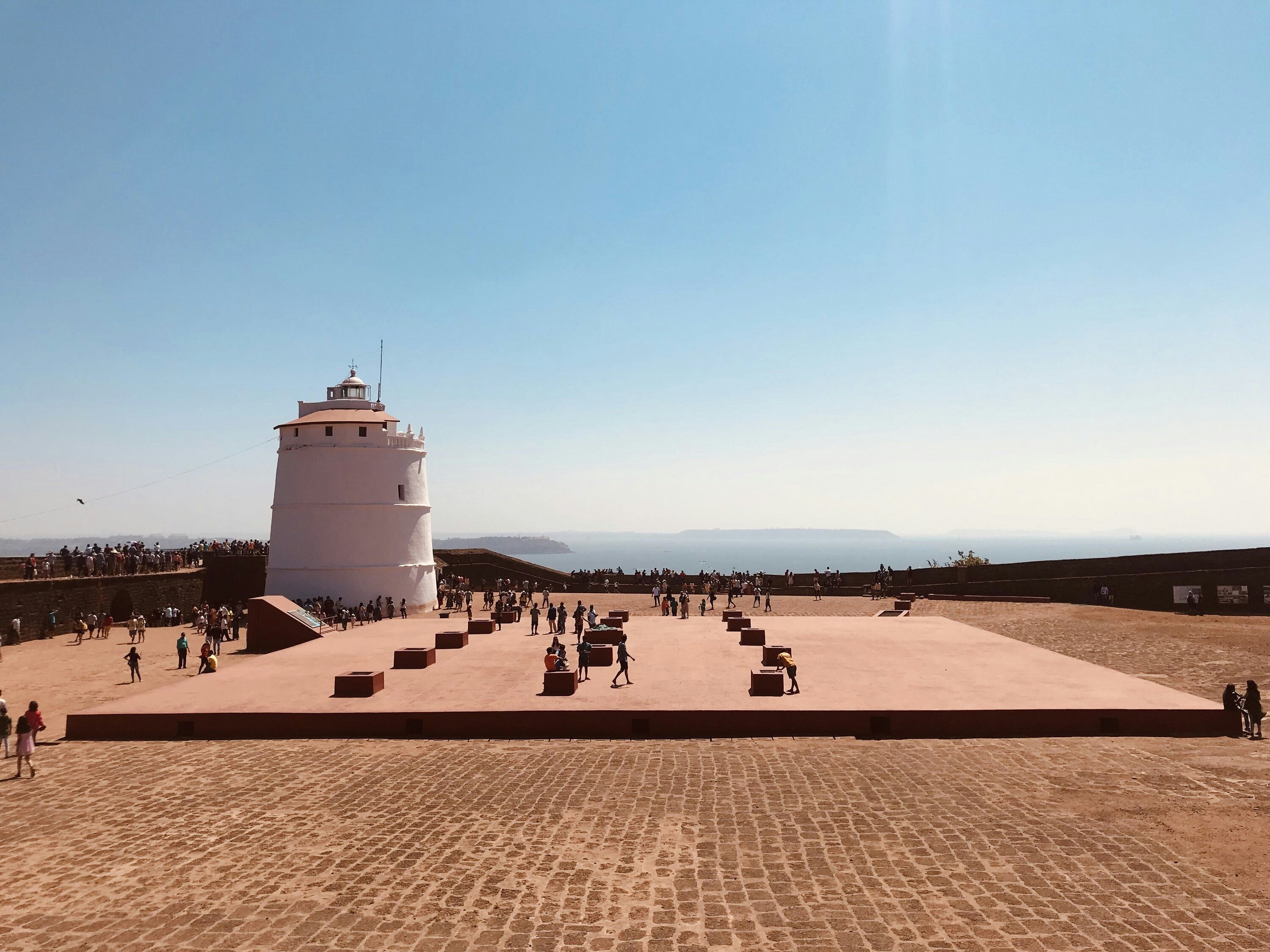 White Lighthouse on a Sunlit Promenade: A Quiet Coastal Moment