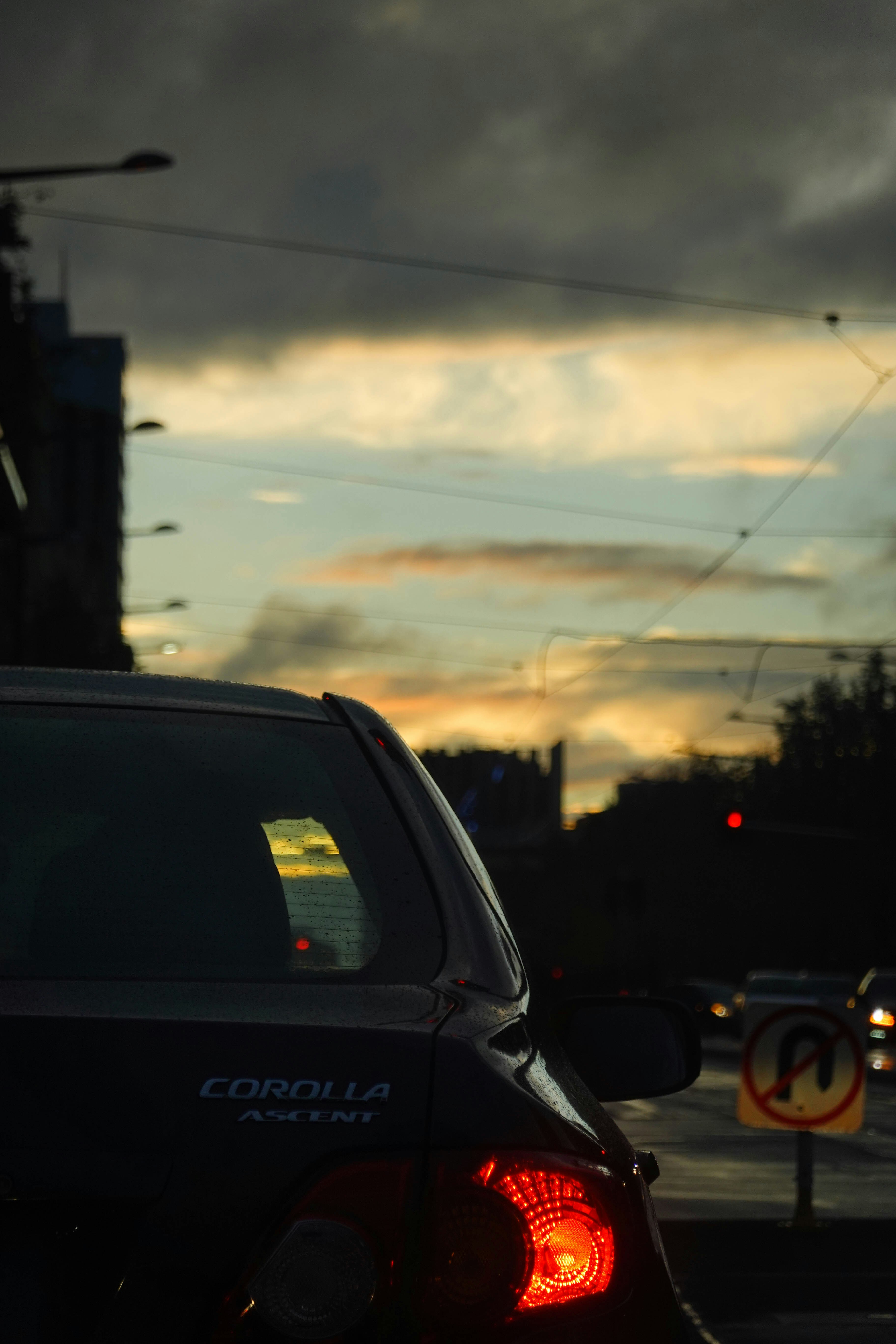 Dusk on the Line: Red Tail Lights and Wires Over a Corolla