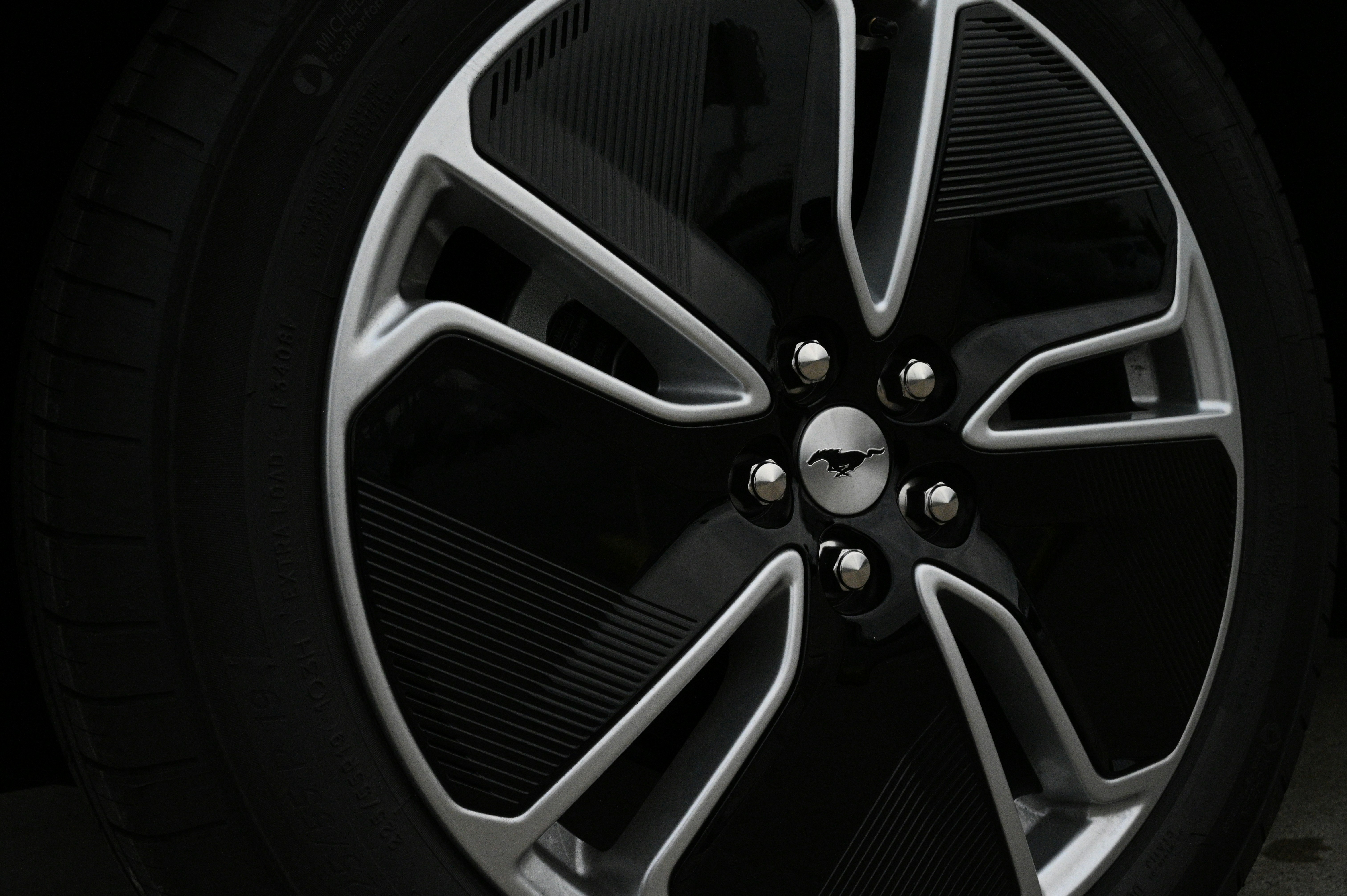 Angular Alloy: close-up of a sculpted wheel with gunmetal spokes and gleaming center badge