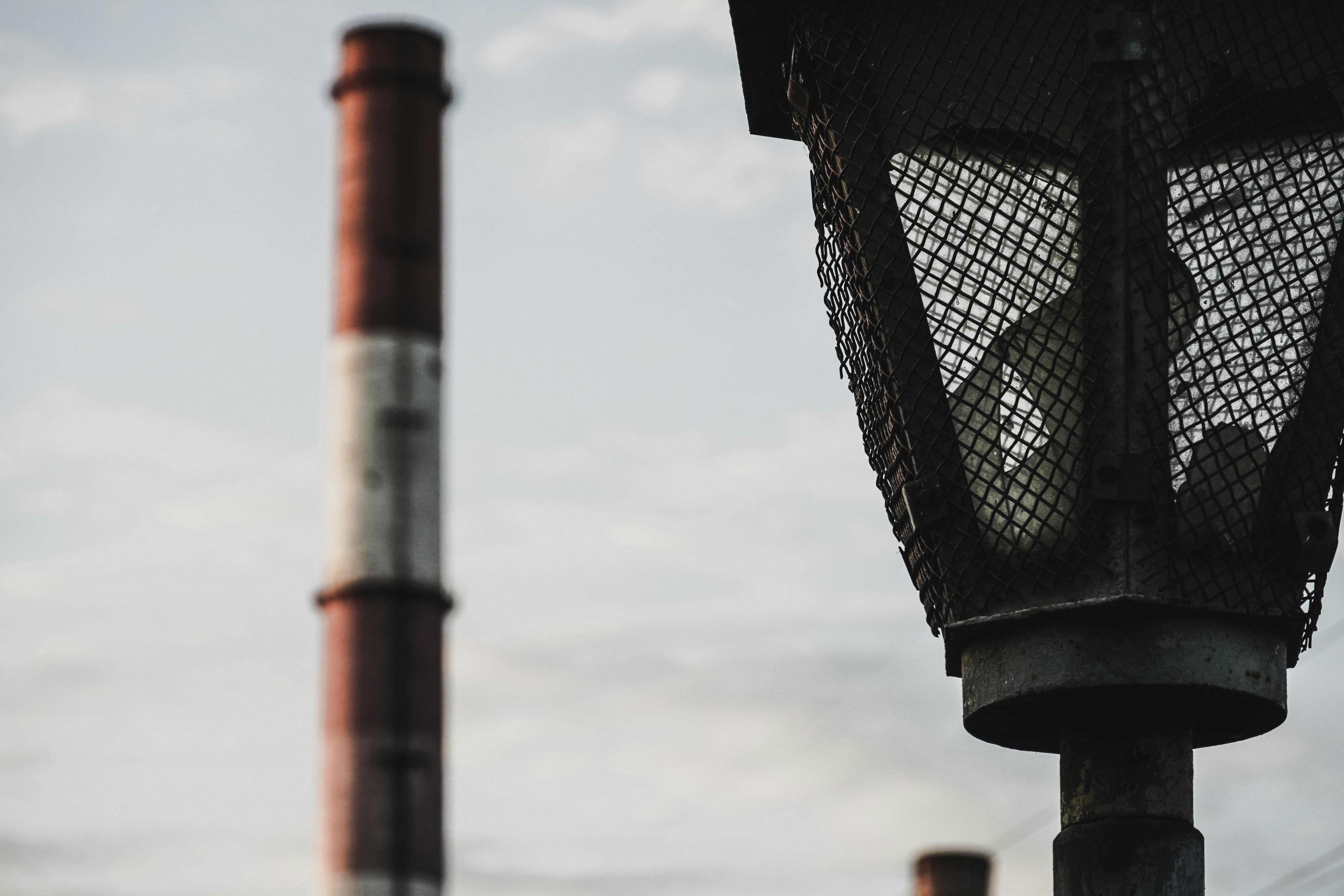 Rusted Lantern, Distant Chimney: A Quiet Industrial Portrait in Daylight