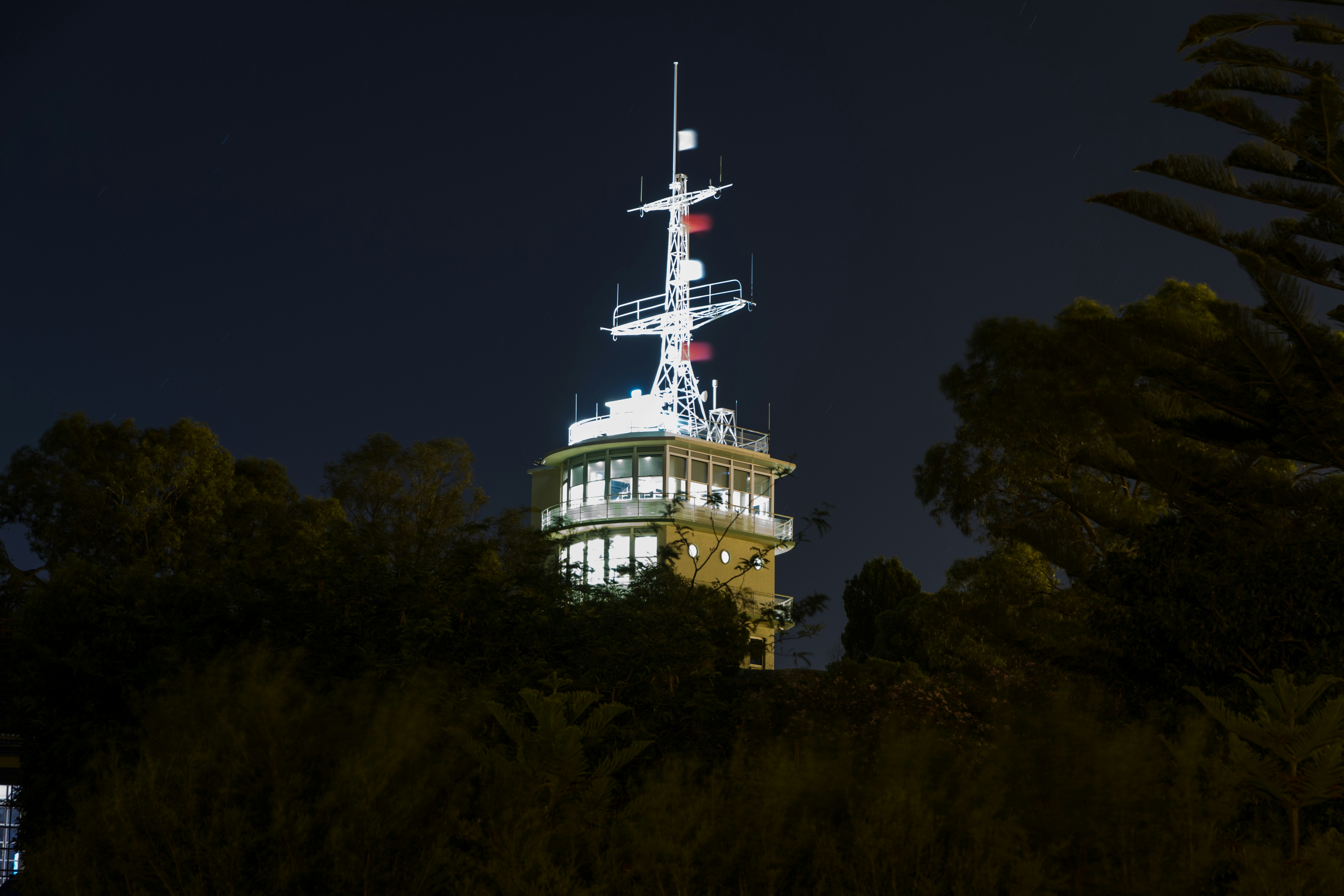 Midnight Beacon Above the Pines: An Illuminated Control Tower Pierces the Night