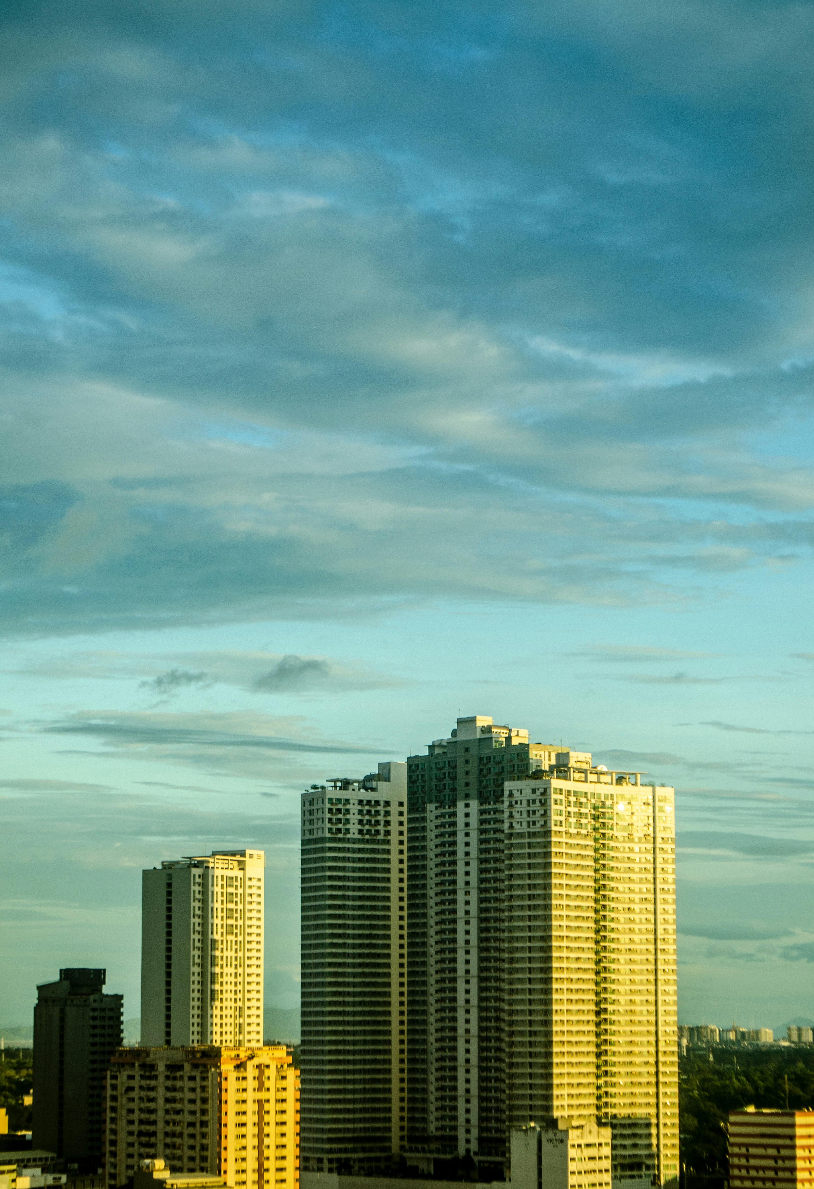 Skyline of modern high-rise buildings under a dynamic sky, showcasing architectural diversity and the interplay of light. 