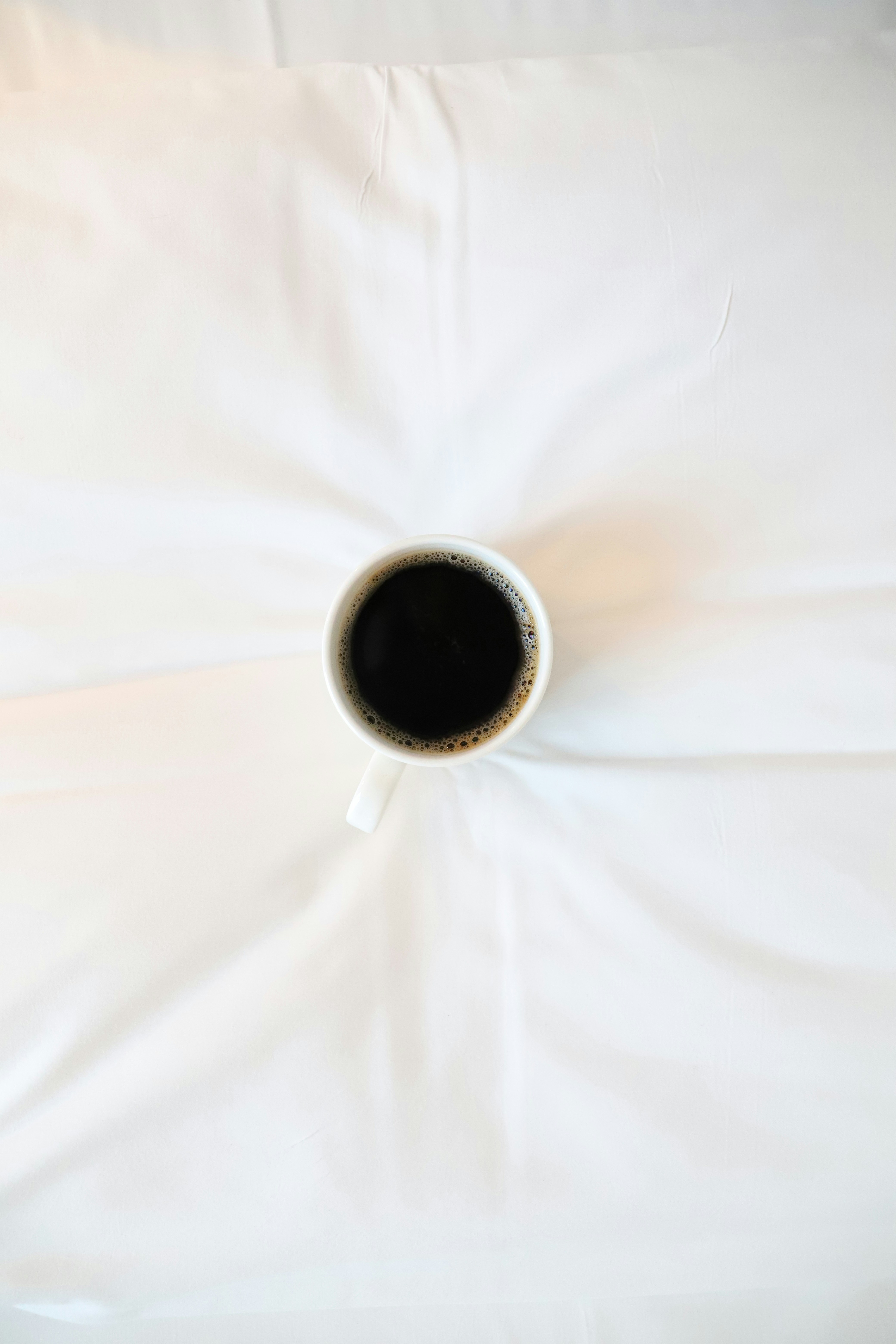 a cup of coffee sitting on top of a white sheet