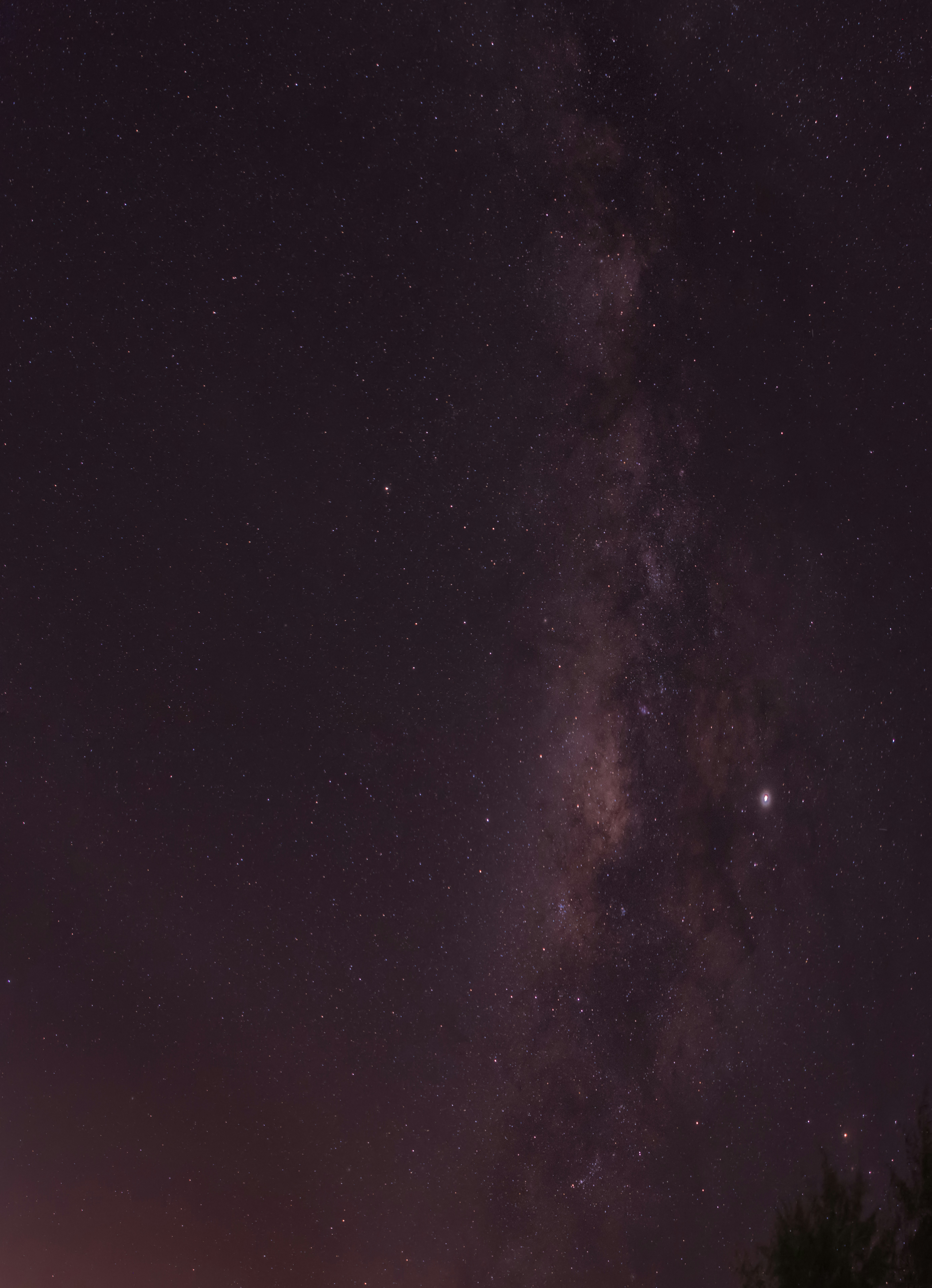 Vast night sky filled with a dense array of stars and the Milky Way, showcasing the beauty of the cosmos. A serene landscape below adds depth to the celestial view.