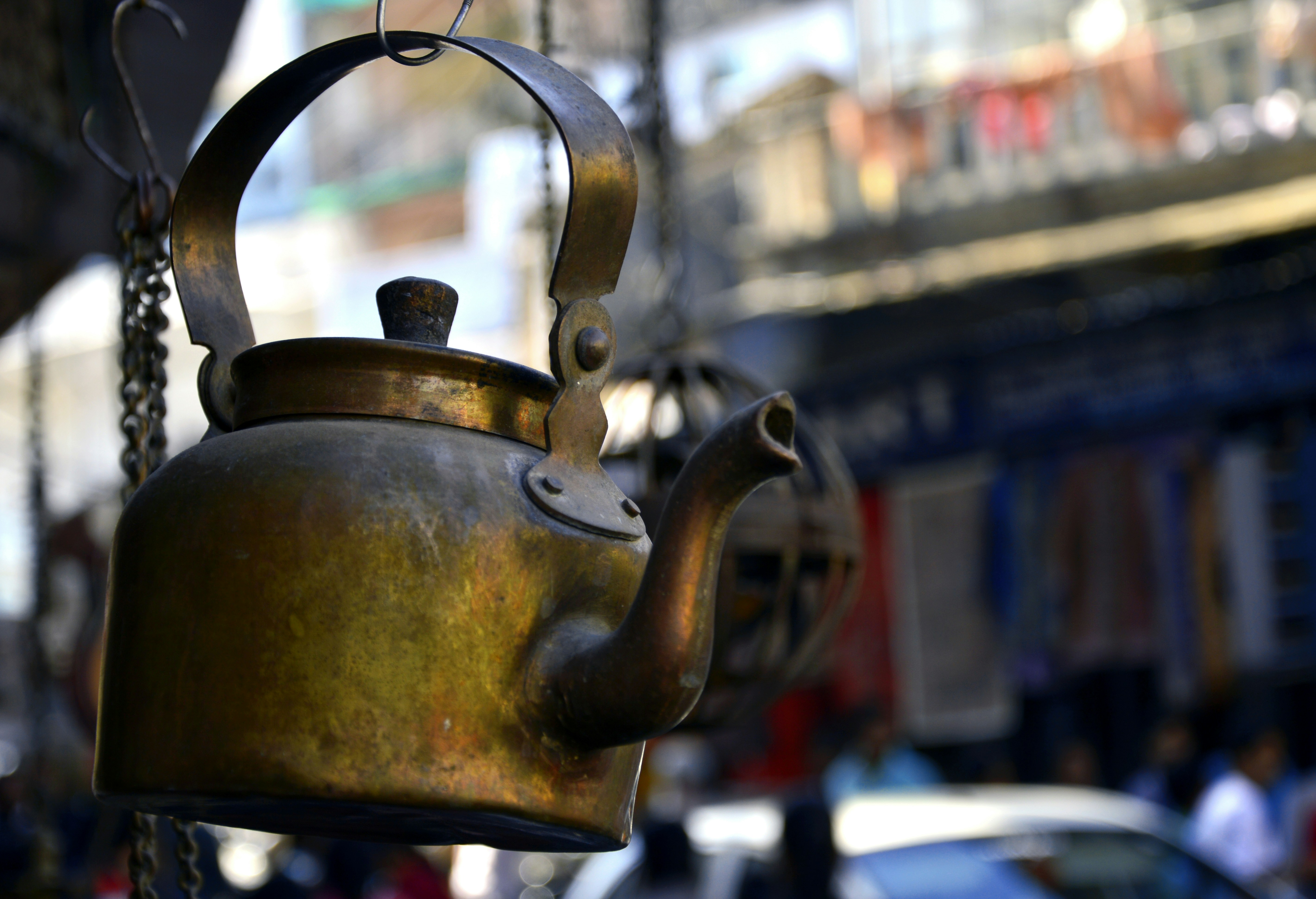 Suspended Copper Kettle: a weathered relic framed by a bustling street