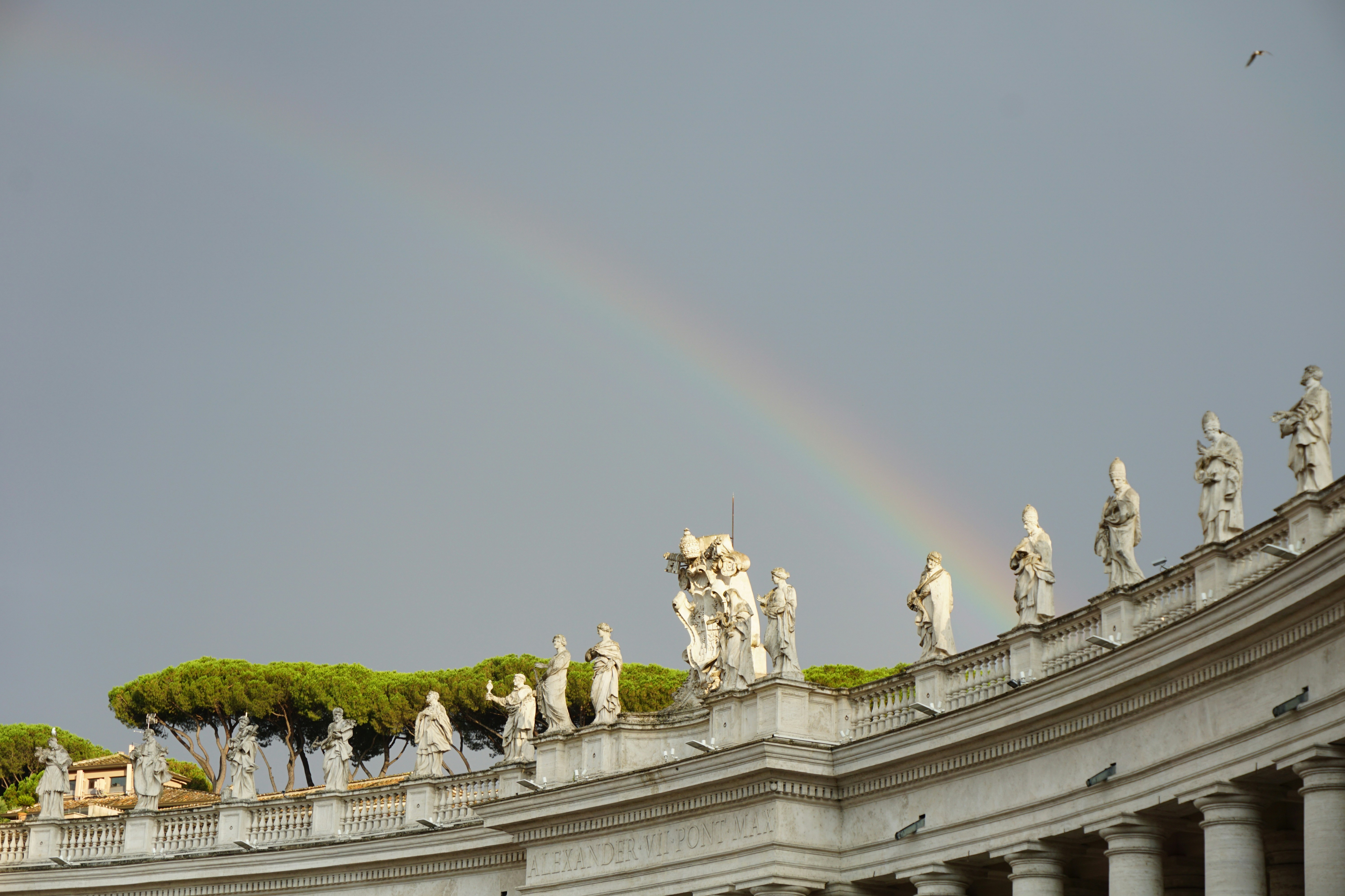 A rainbow in the sky over a building with statues photo – Free Vatican ...