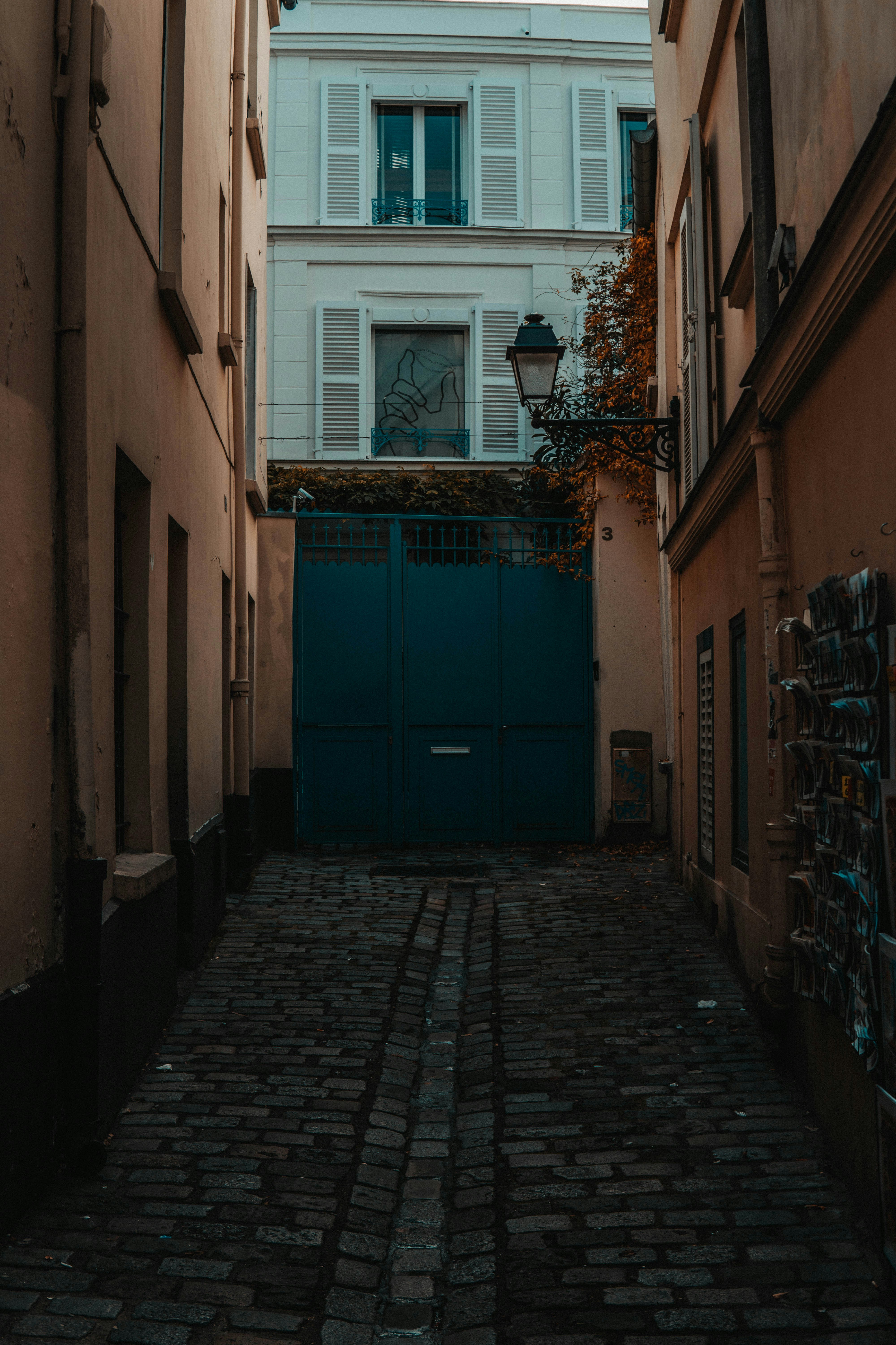 Blue Gate at the End of a Narrow Cobblestone Alley, Framed by Warm Facades