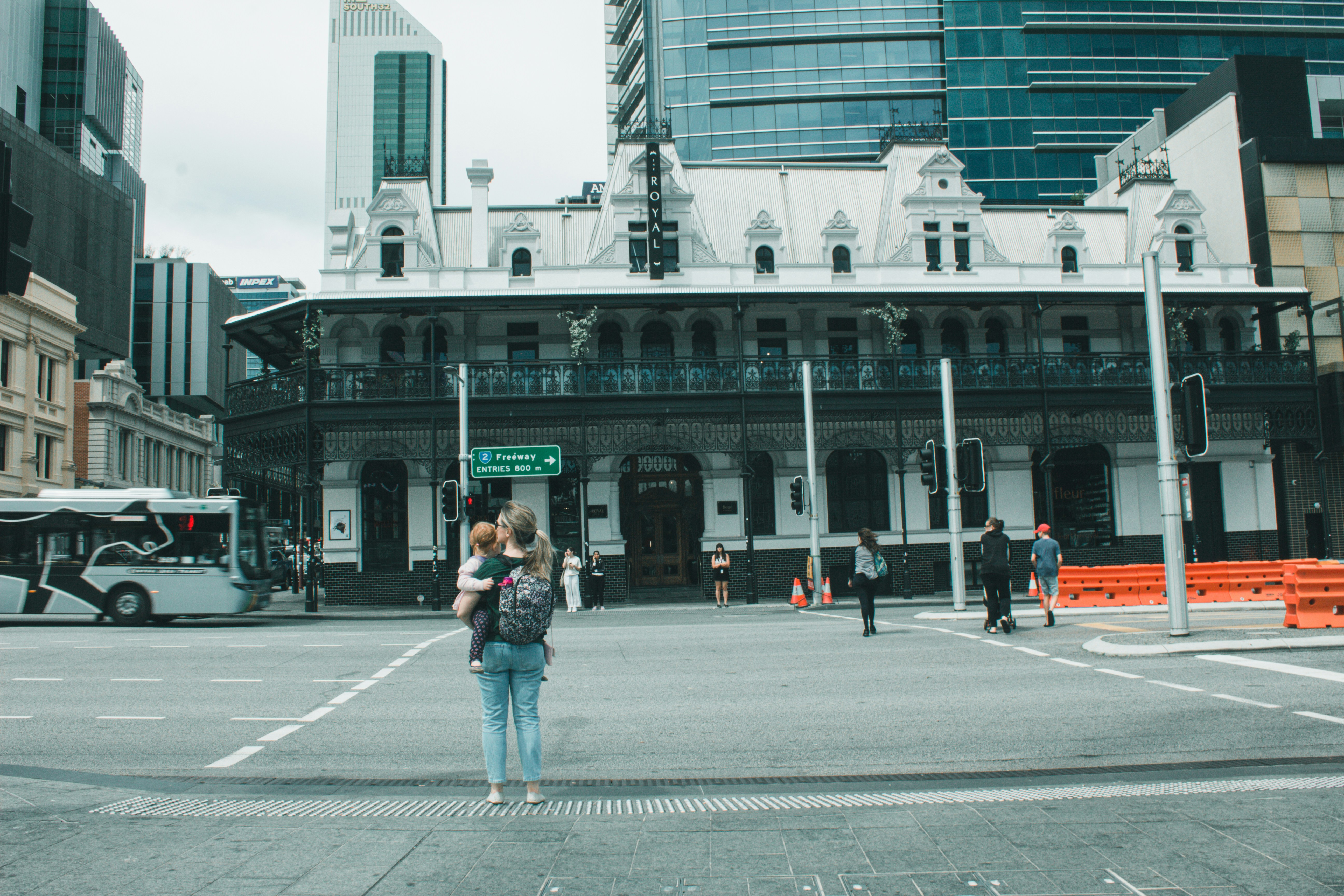 Person standing at a city crosswalk with surrounding traffic and historic architecture.