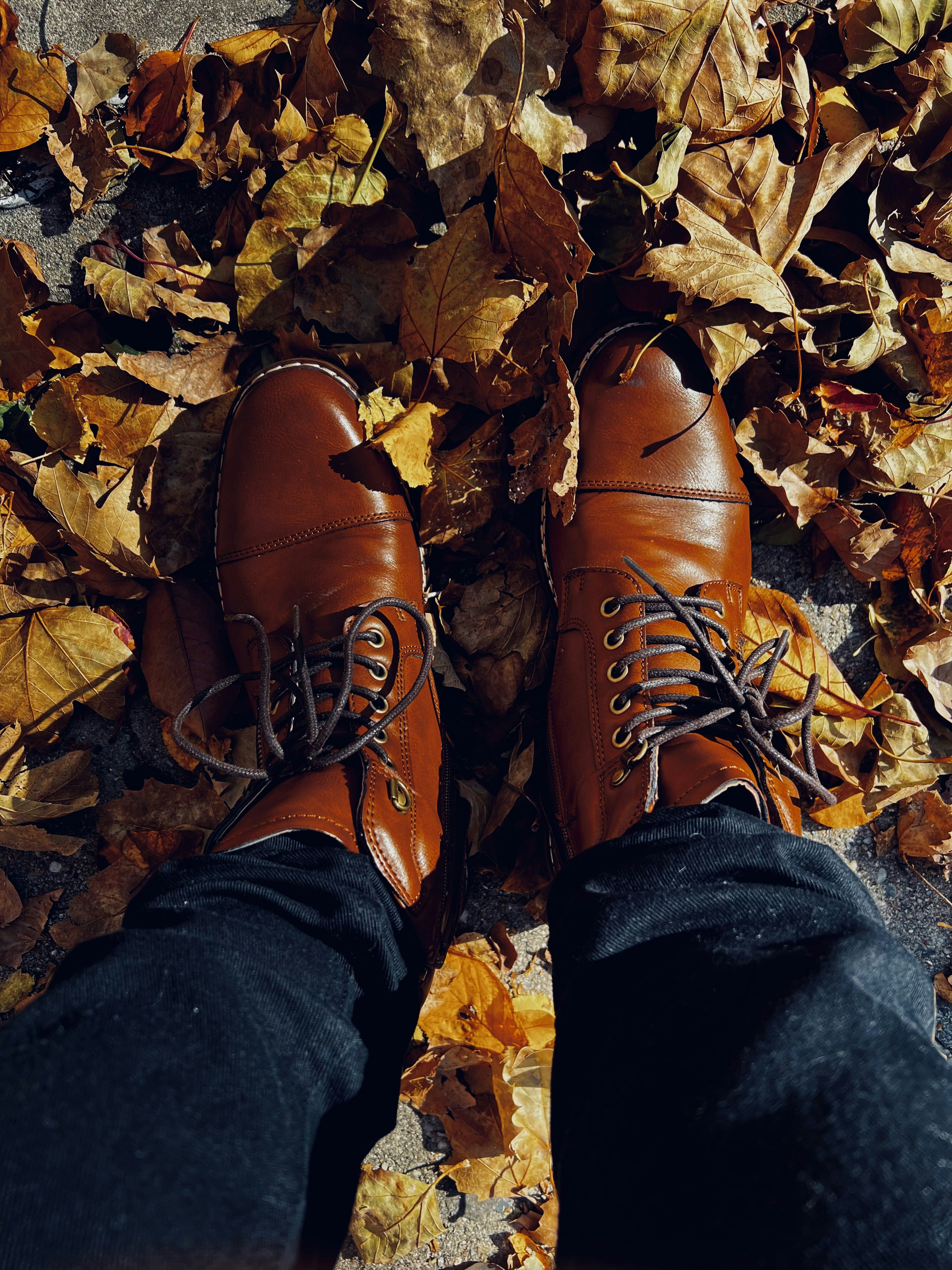 Grounded in Autumn: Brown Leather Boots Amid a Sea of Leaves