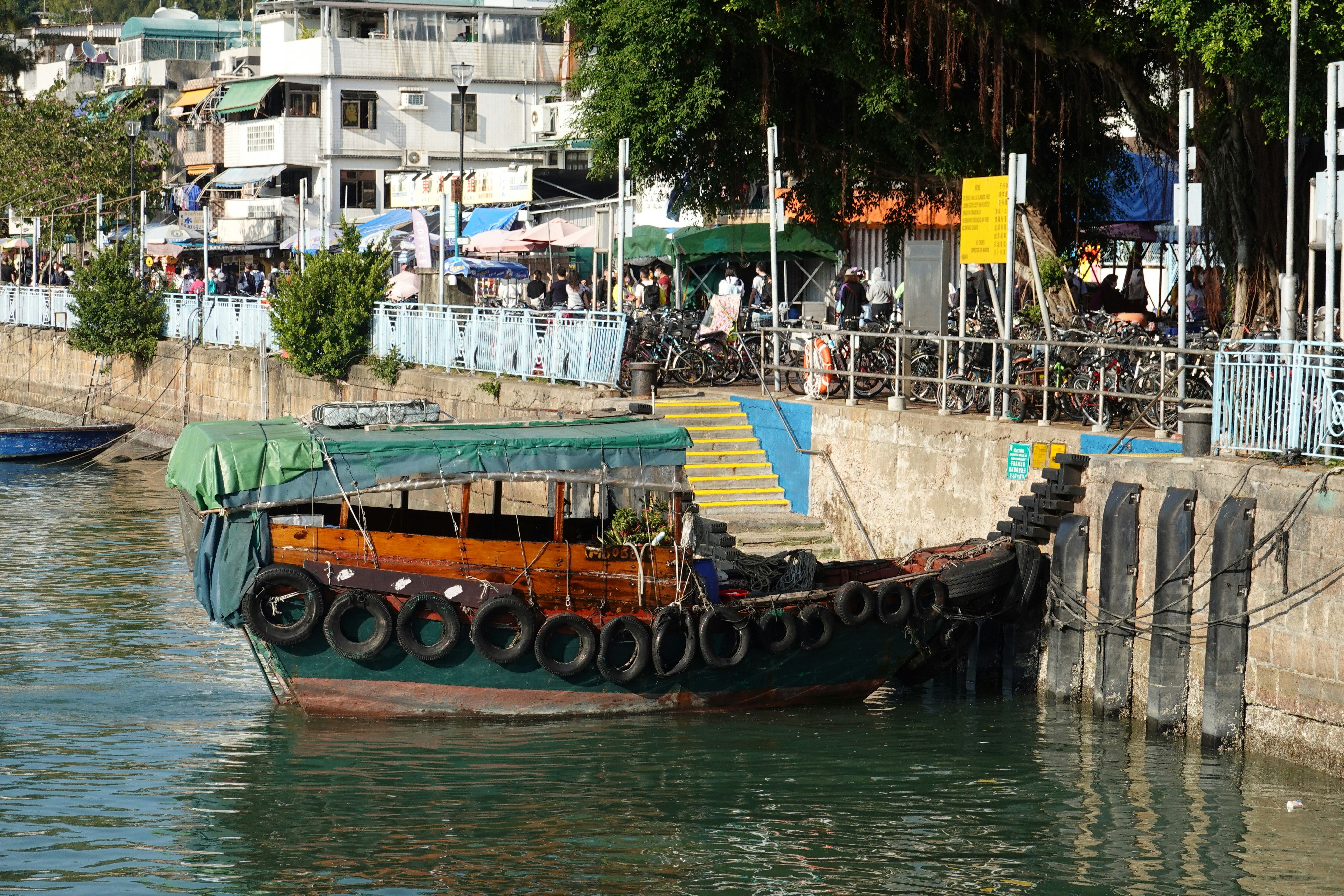 Tire-Fendered Boat Nestled Along a Bustling City Wharf