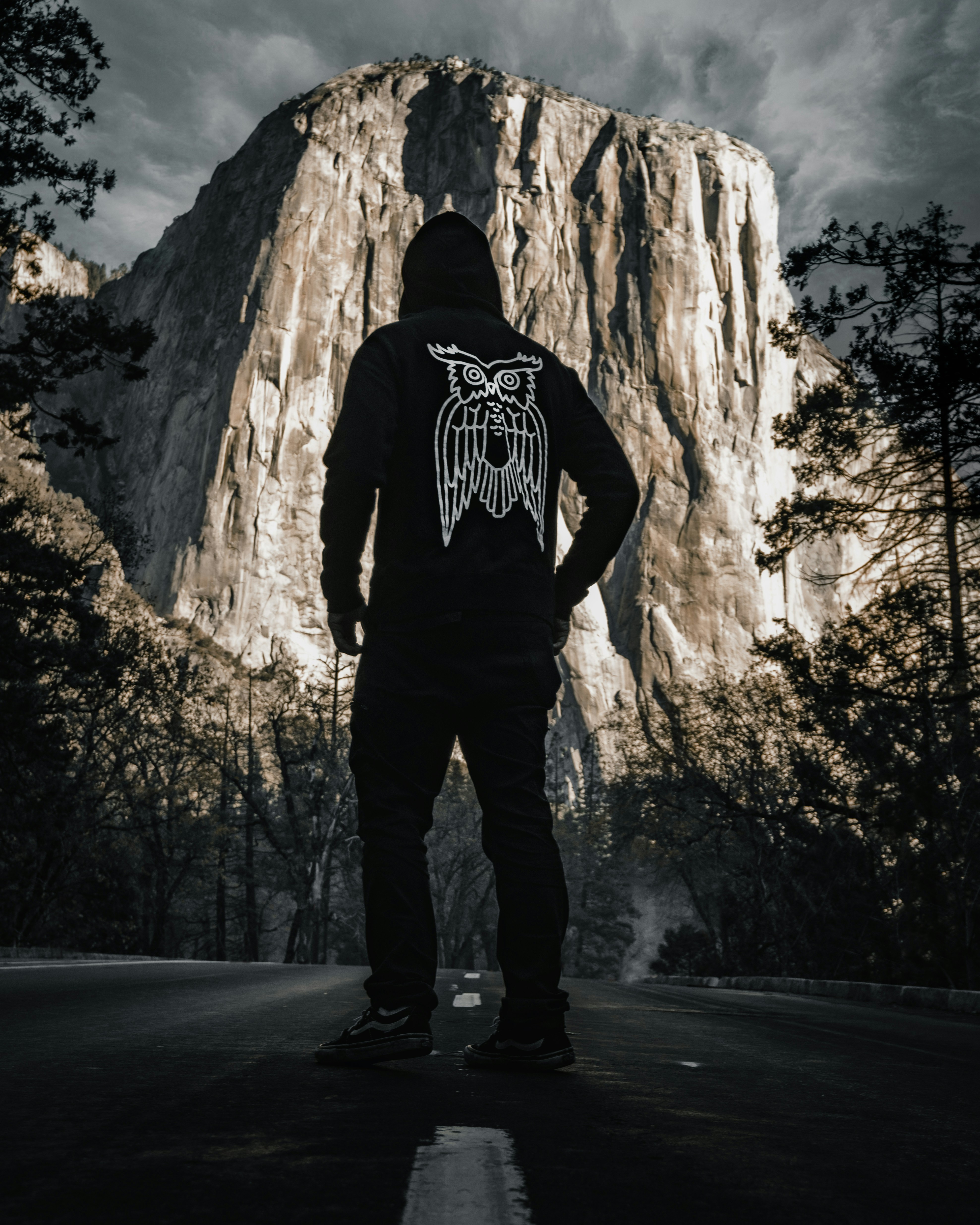 Hooded silhouette on an empty road before a granite colossus