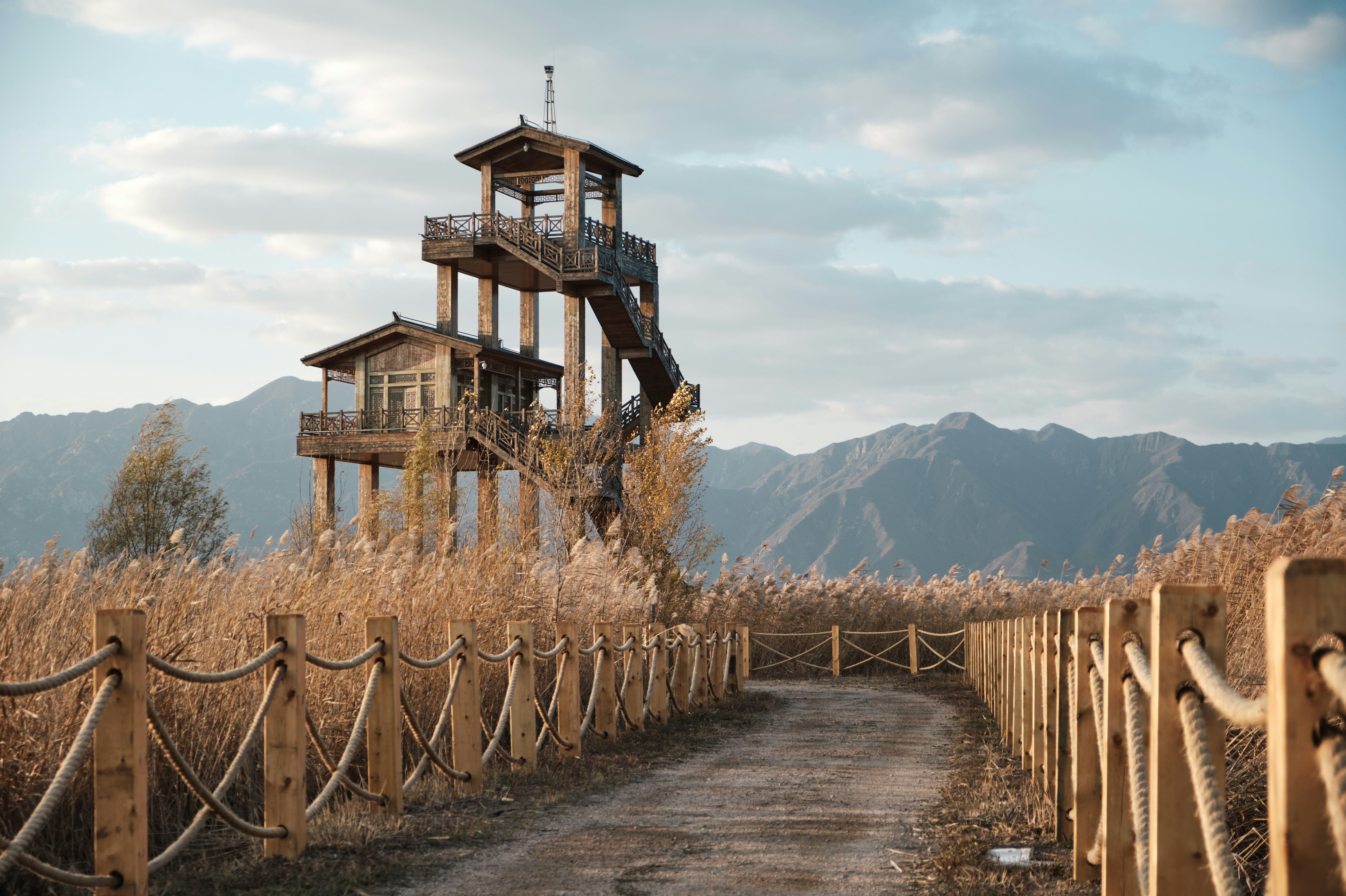 A tall wooden tower sitting on the side of a dirt road photo – Free ...