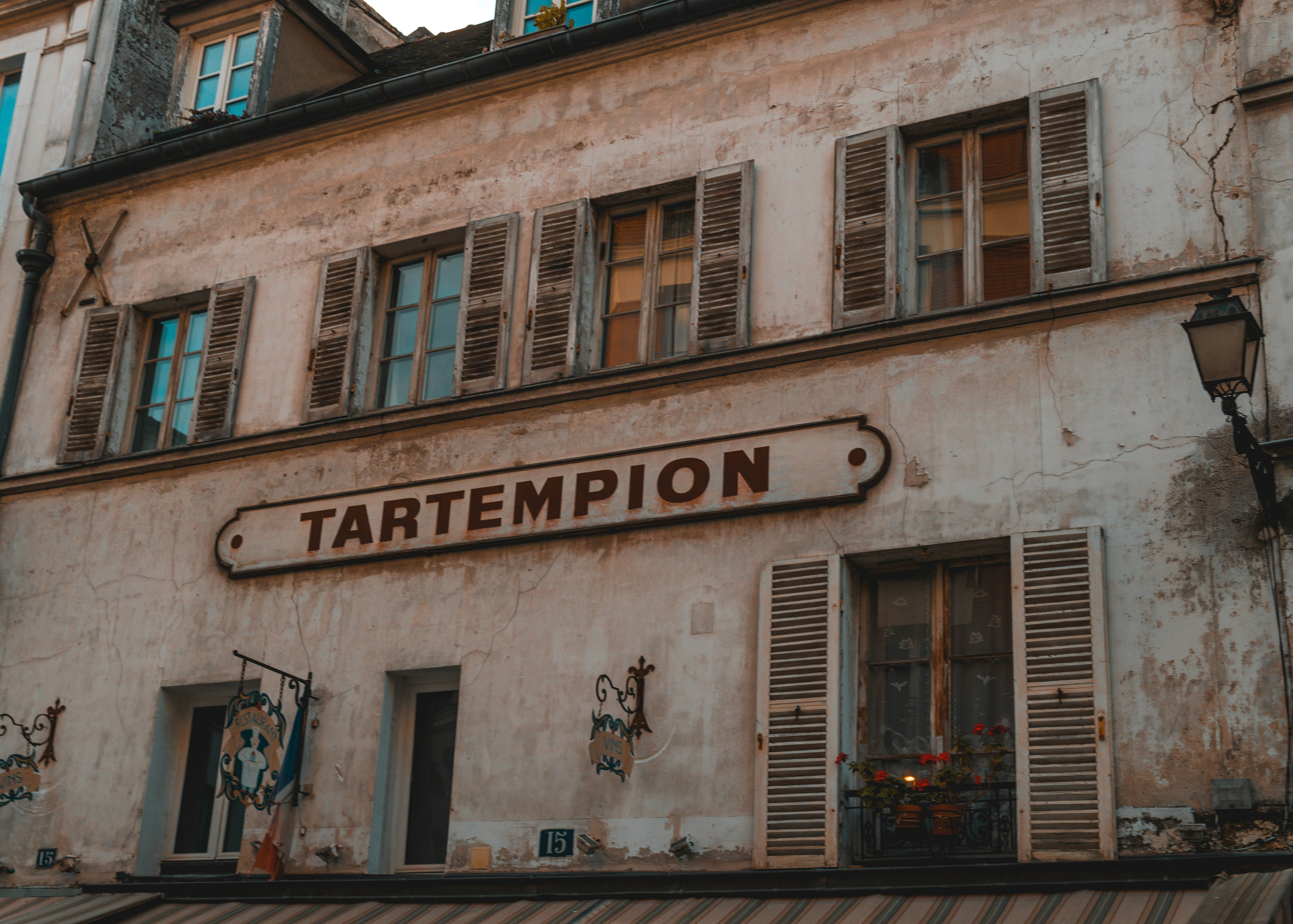 Weathered building with rustic shutters and a sign reading 'Tartempion.'