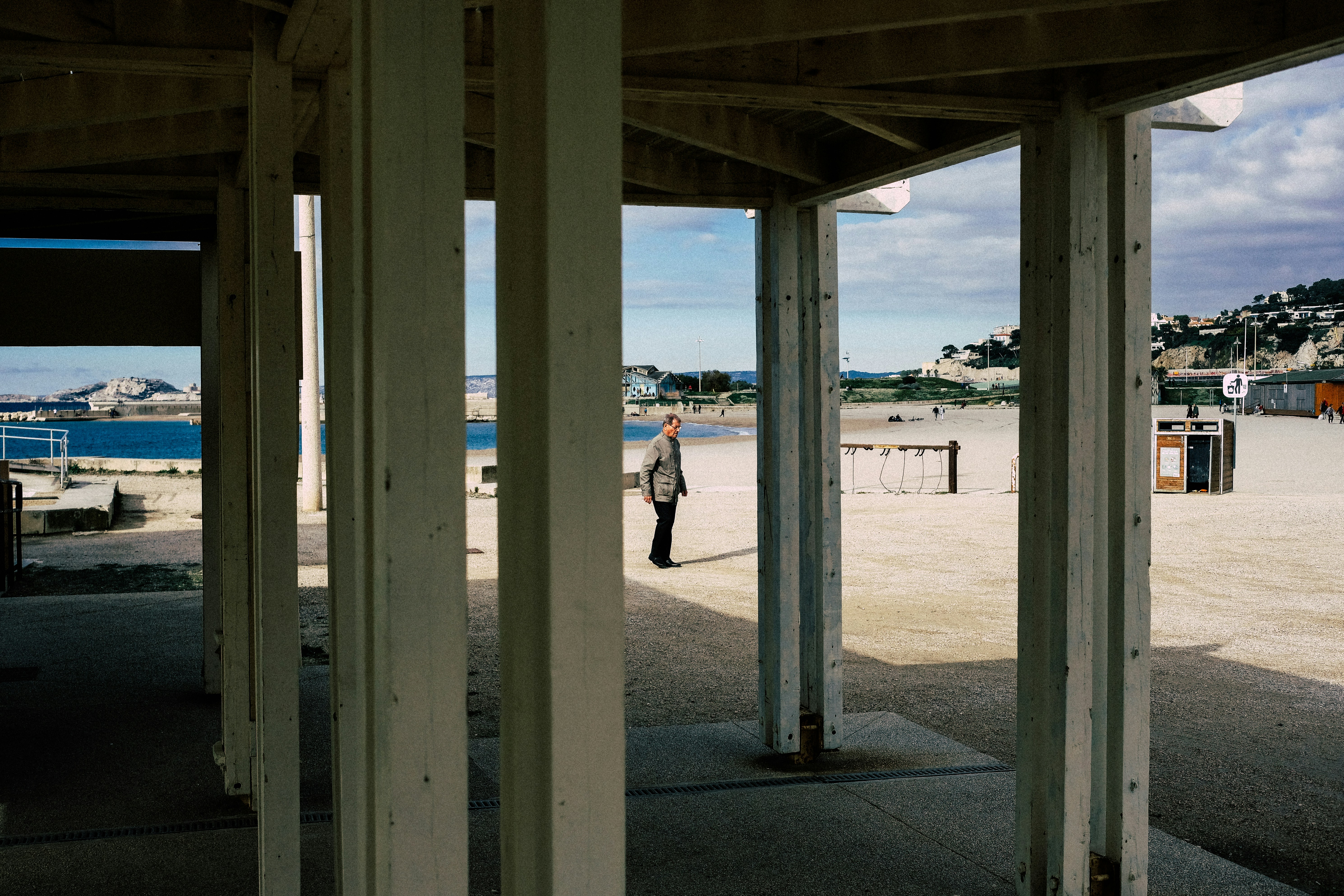 A person standing under a wooden structure on a beach photo – Free ...