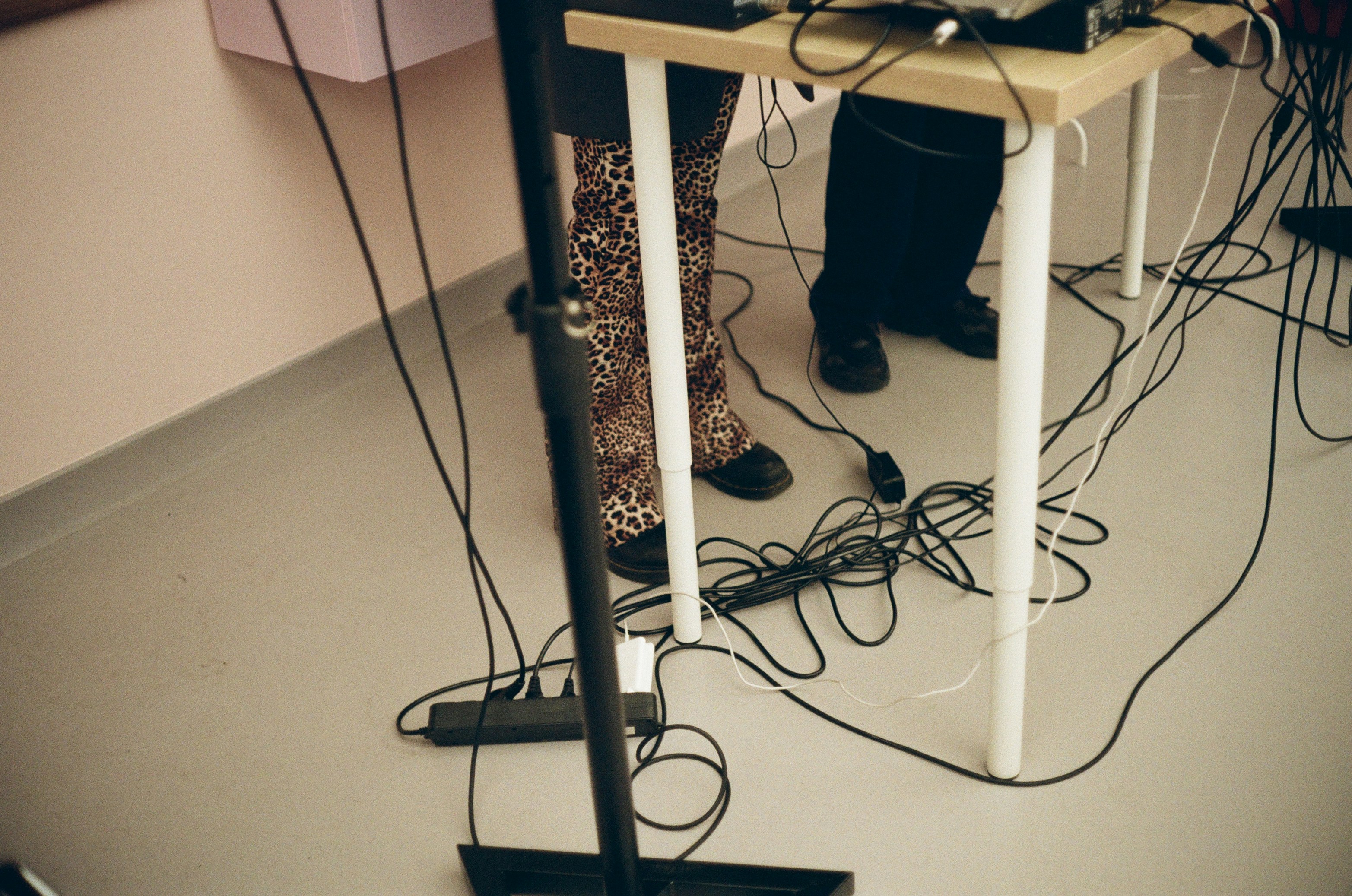 Cables, Legs, and a Leopard-Print Hint Under a Desk