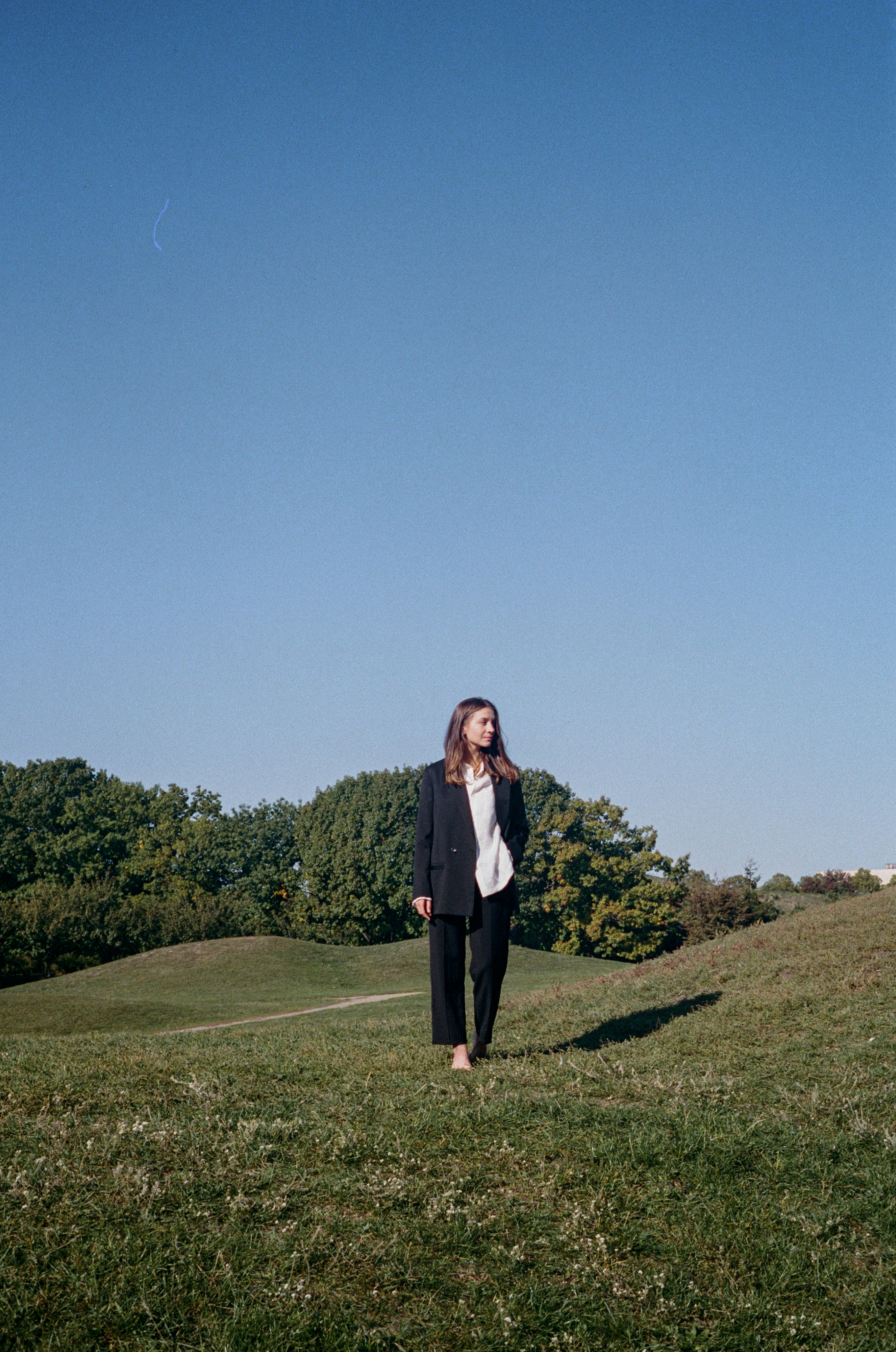 a woman standing in a field with a kite in the sky