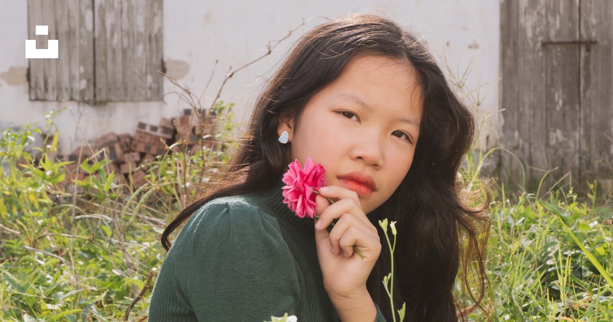 Foto Una Mujer Sentada En Un Campo Con Una Flor En La Mano Imagen