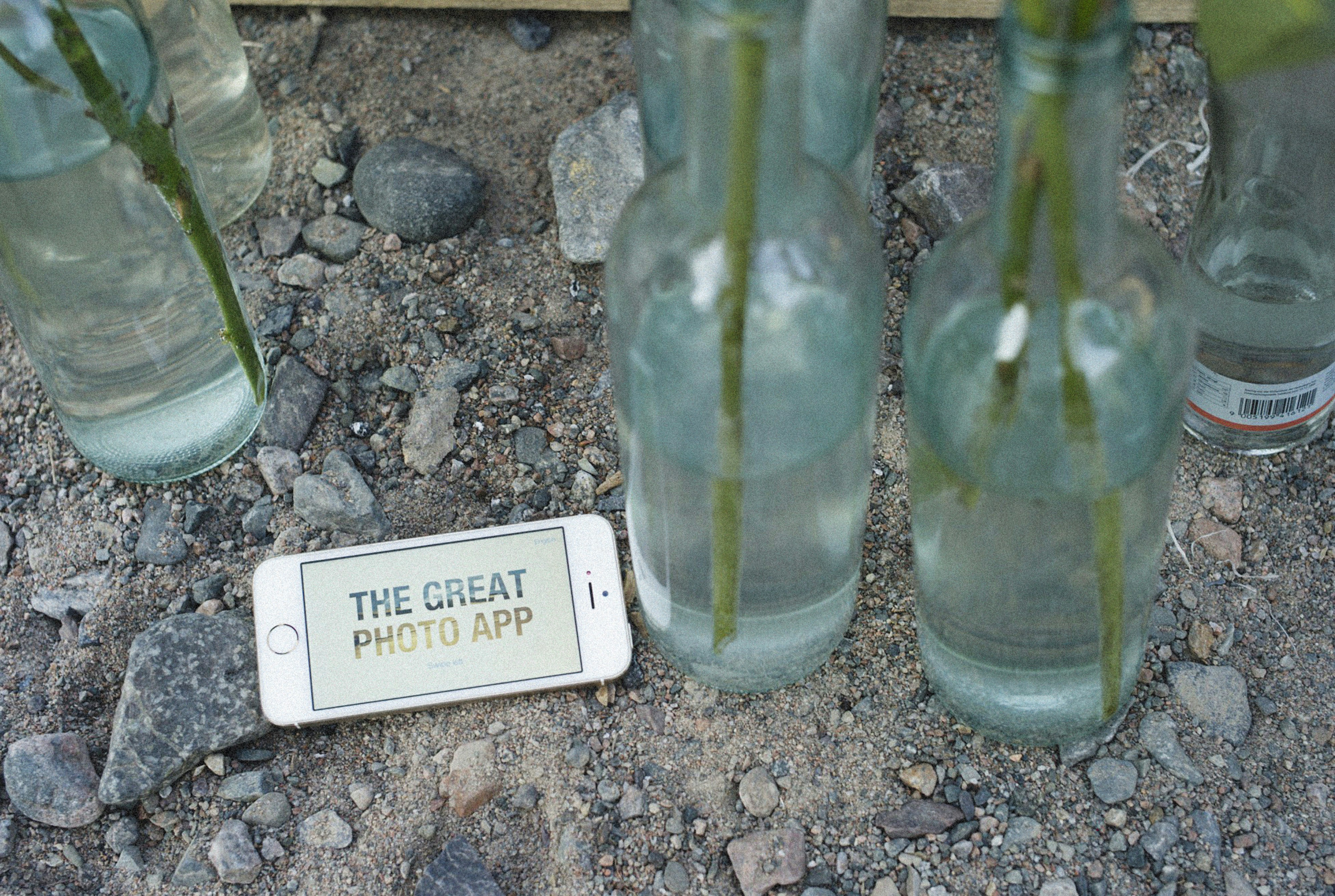 Pebble Ground Still Life: Bottles Framing The Great Photo App on Screen