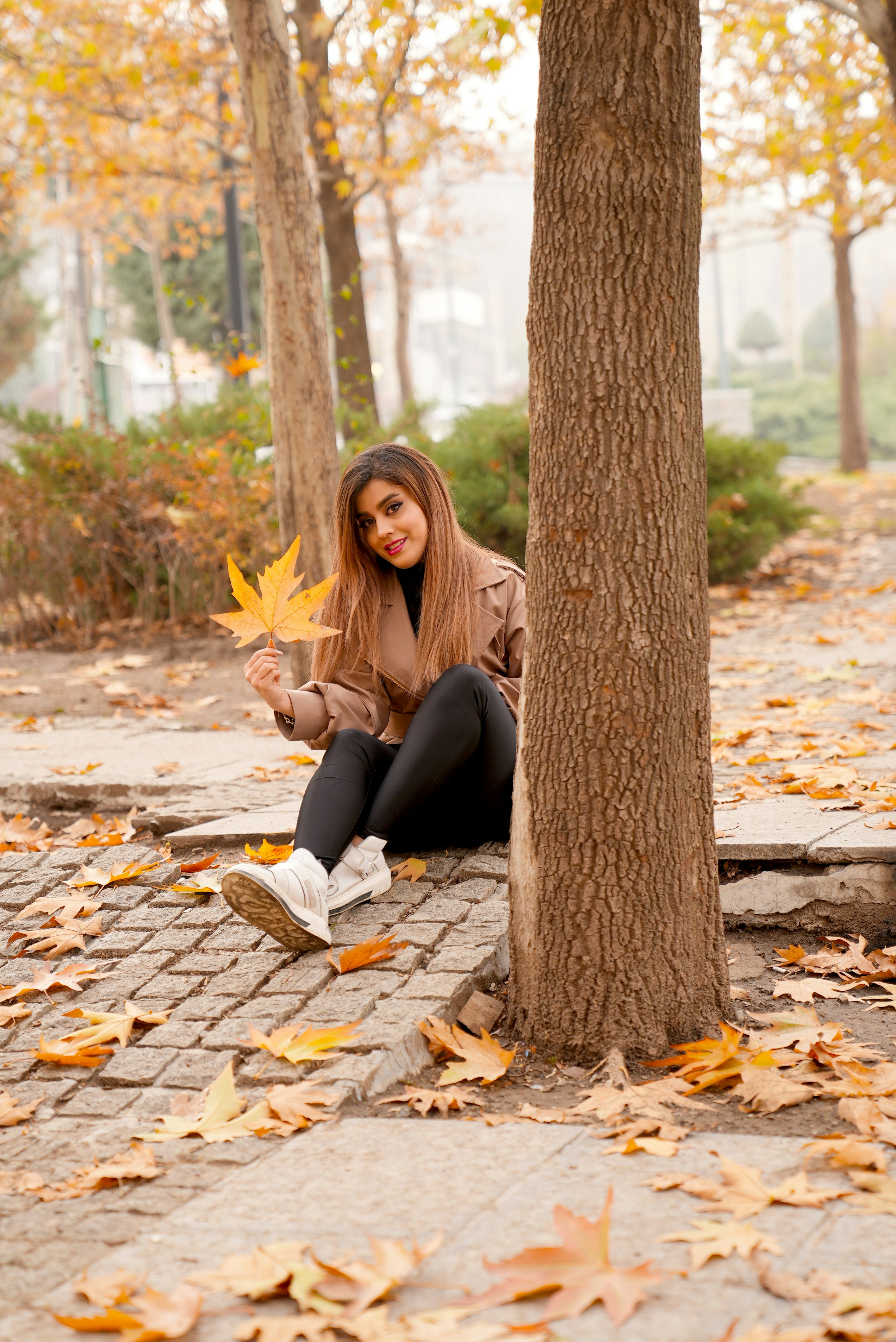 Una mujer sentada en el suelo junto a un árbol foto – Imagen de Marrón ...