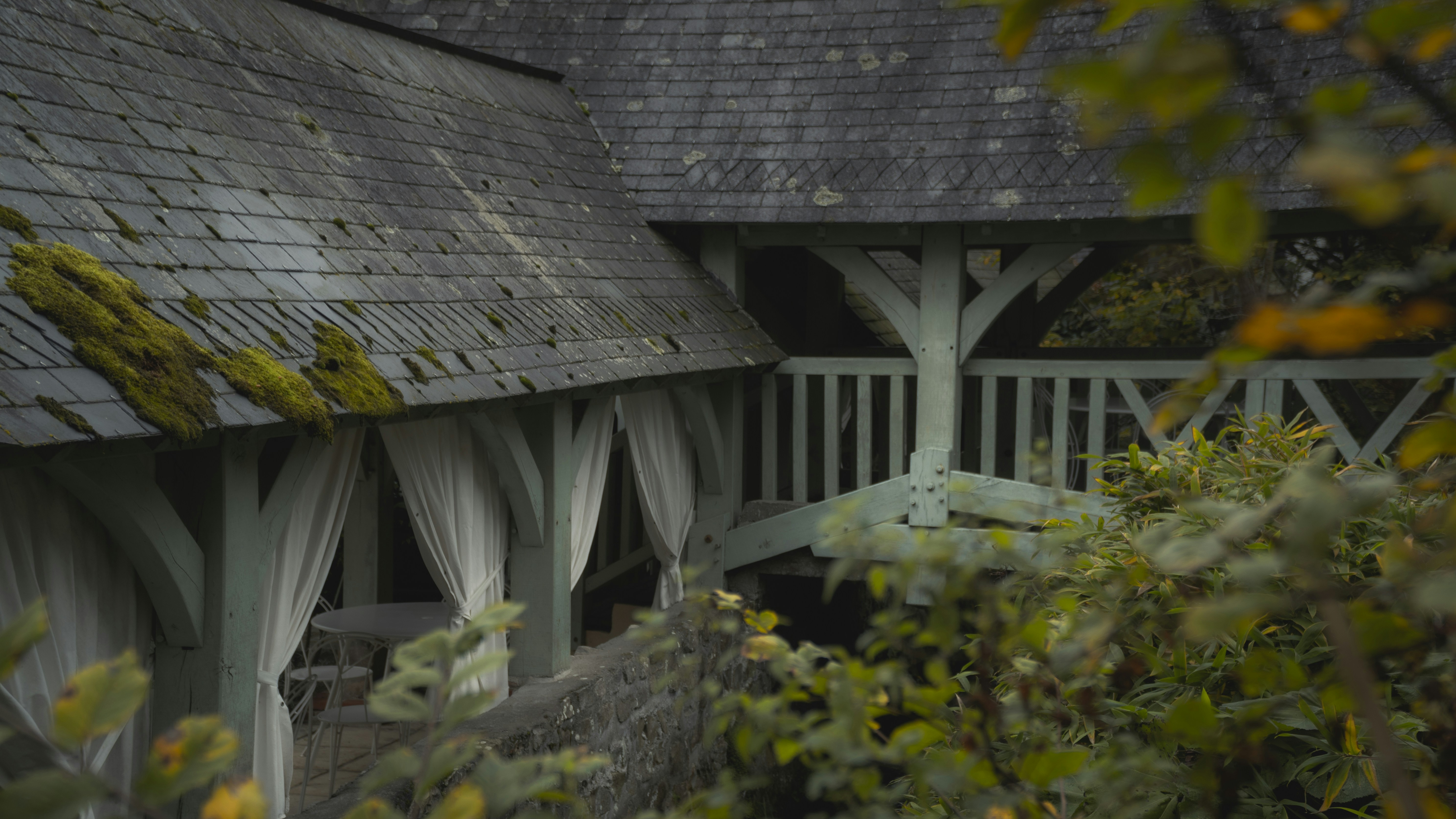 Charming wooden structure nestled among lush greenery, showcasing delicate curtains and moss-covered roof. A serene escape into nature's embrace.