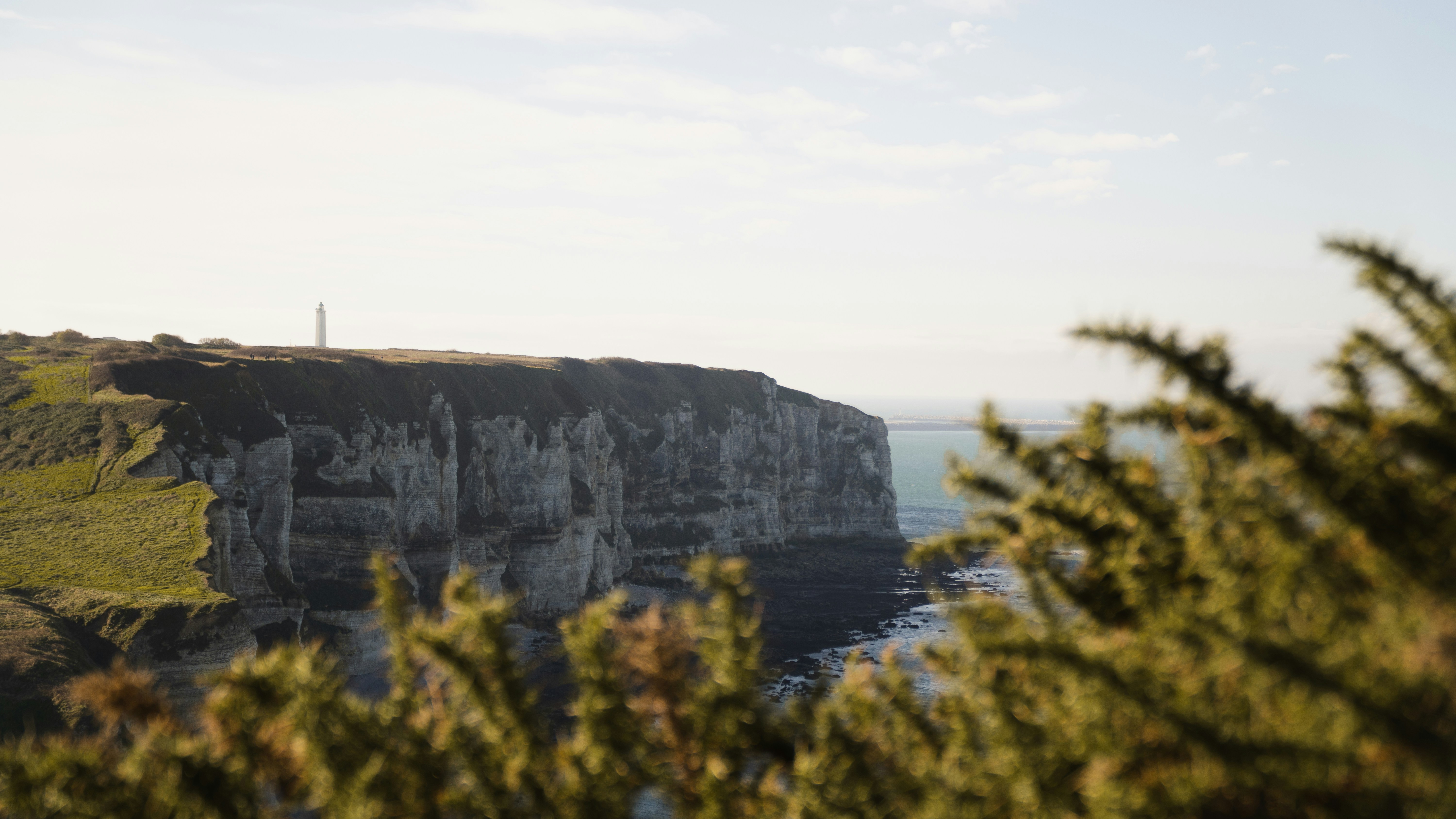 a view of a cliff with a lighthouse in the distance