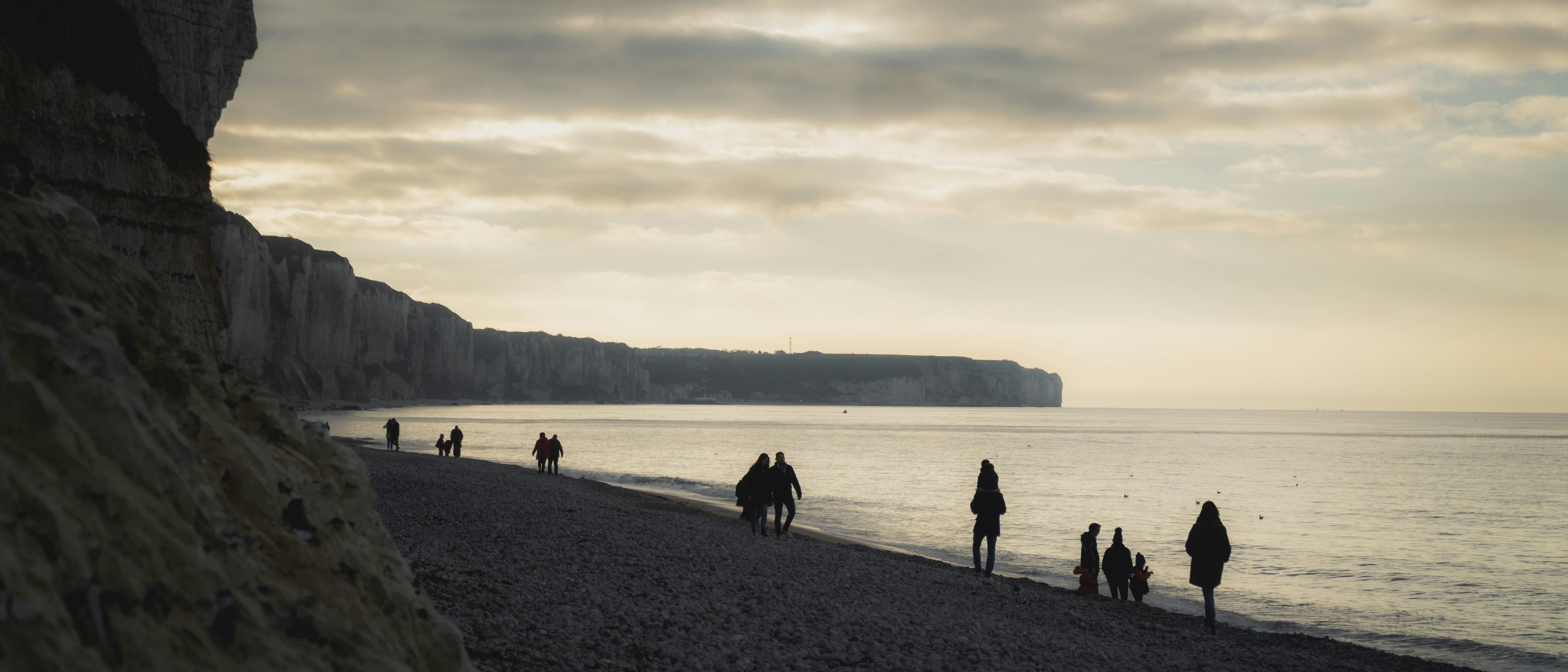 Dusk on the Cliffside: silhouettes tracing the pebbled shoreline