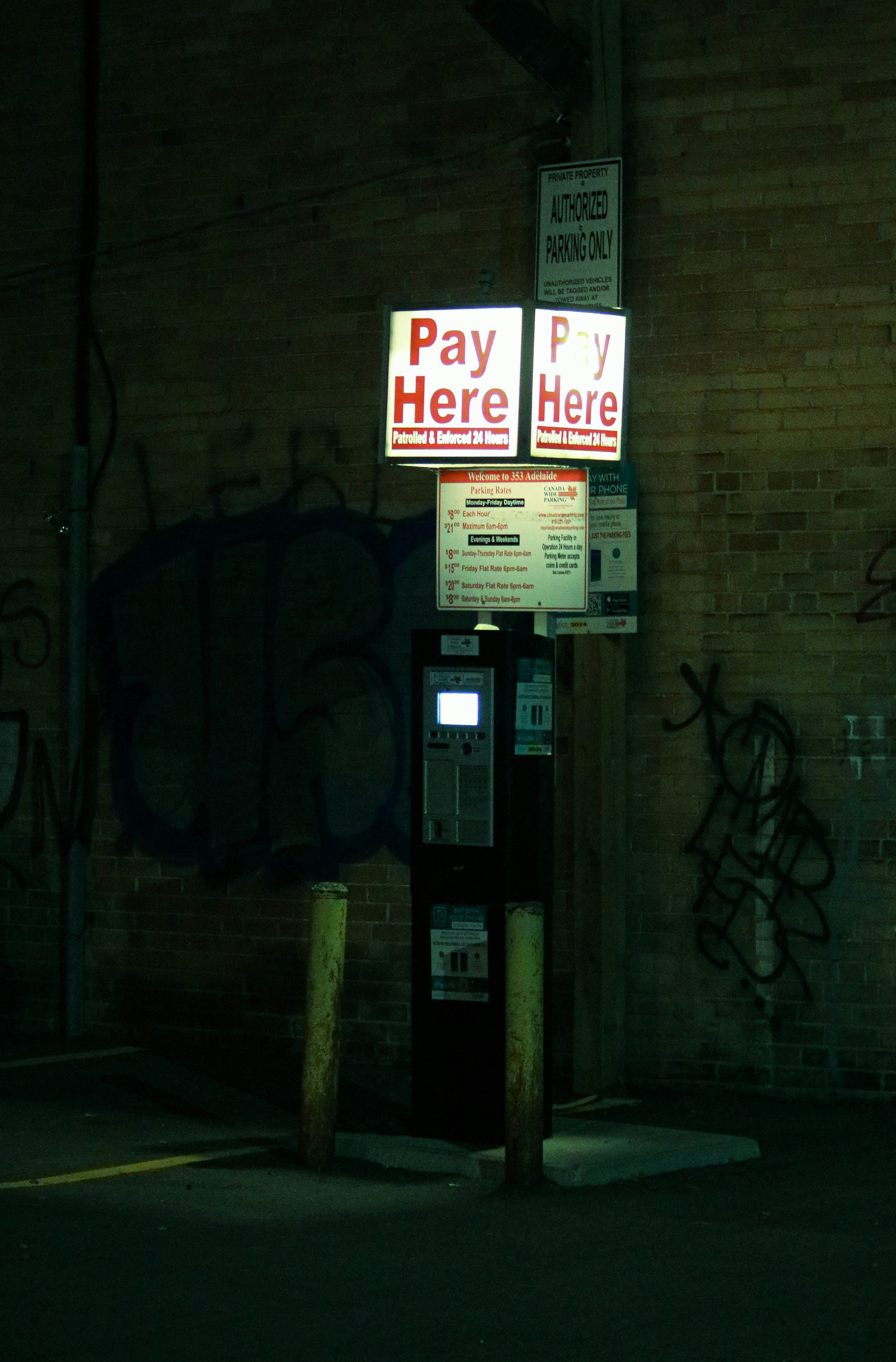 a pay here sign in front of a brick wall