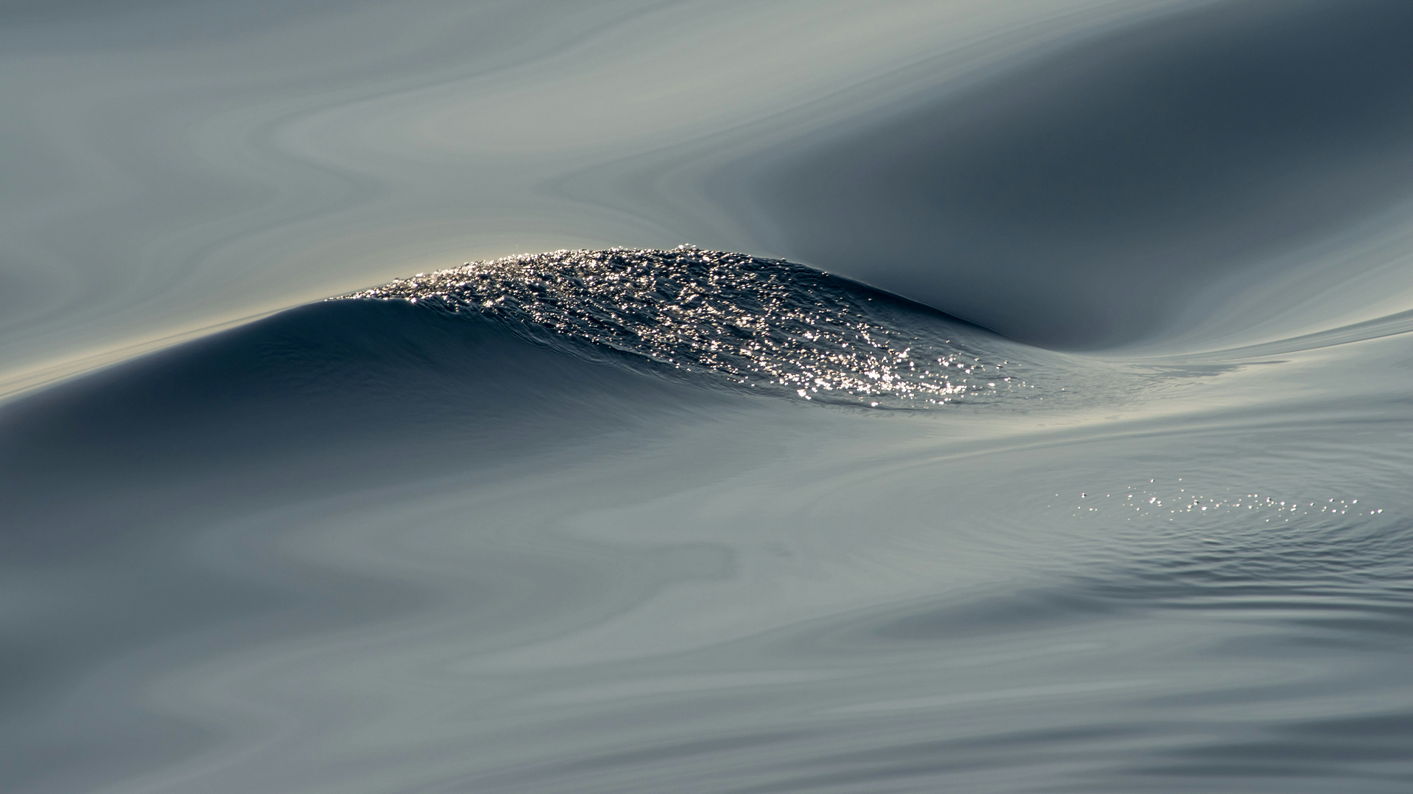Close-up of a silky water surface with a glittering crest catching light.