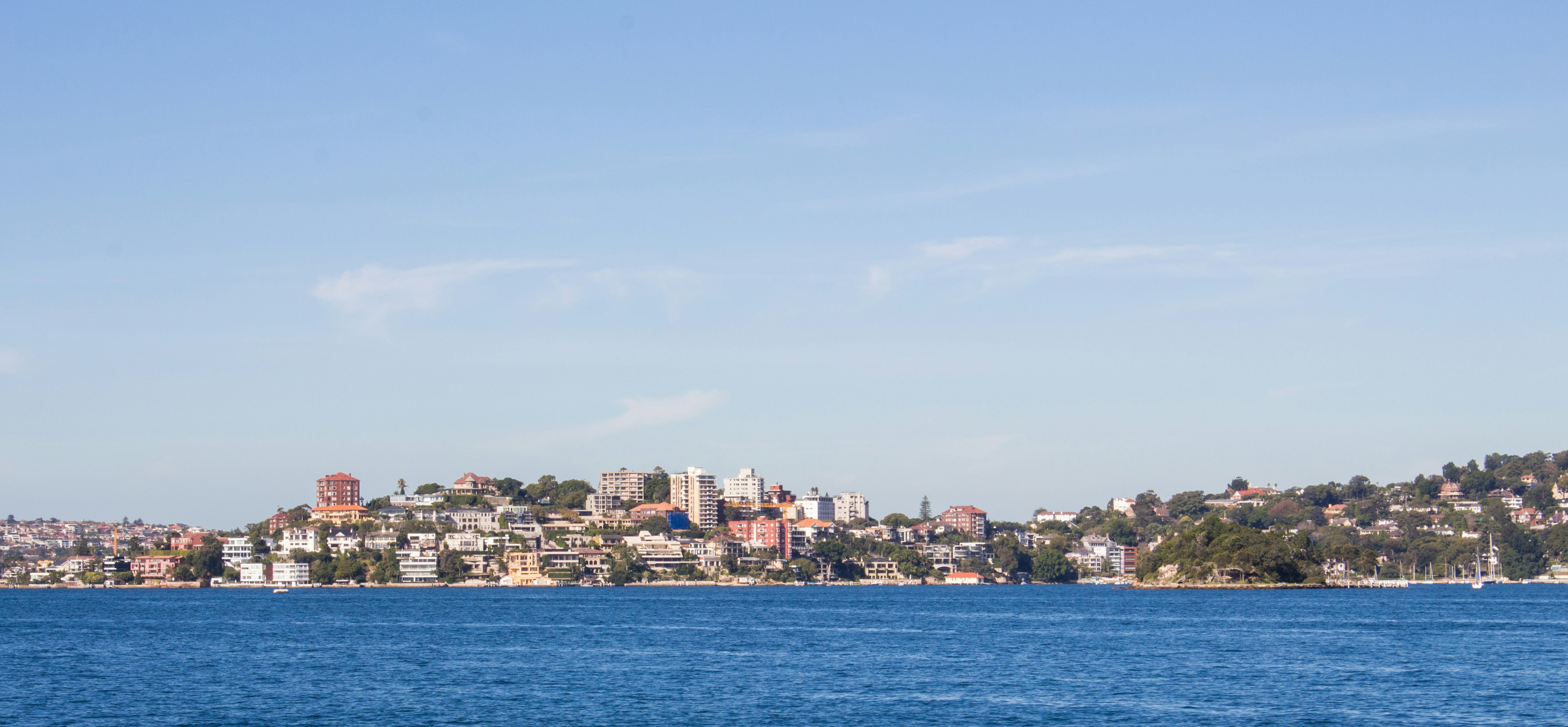 Vibrant coastal community with colorful buildings lining the shore, framed by tranquil blue waters and a clear sky.