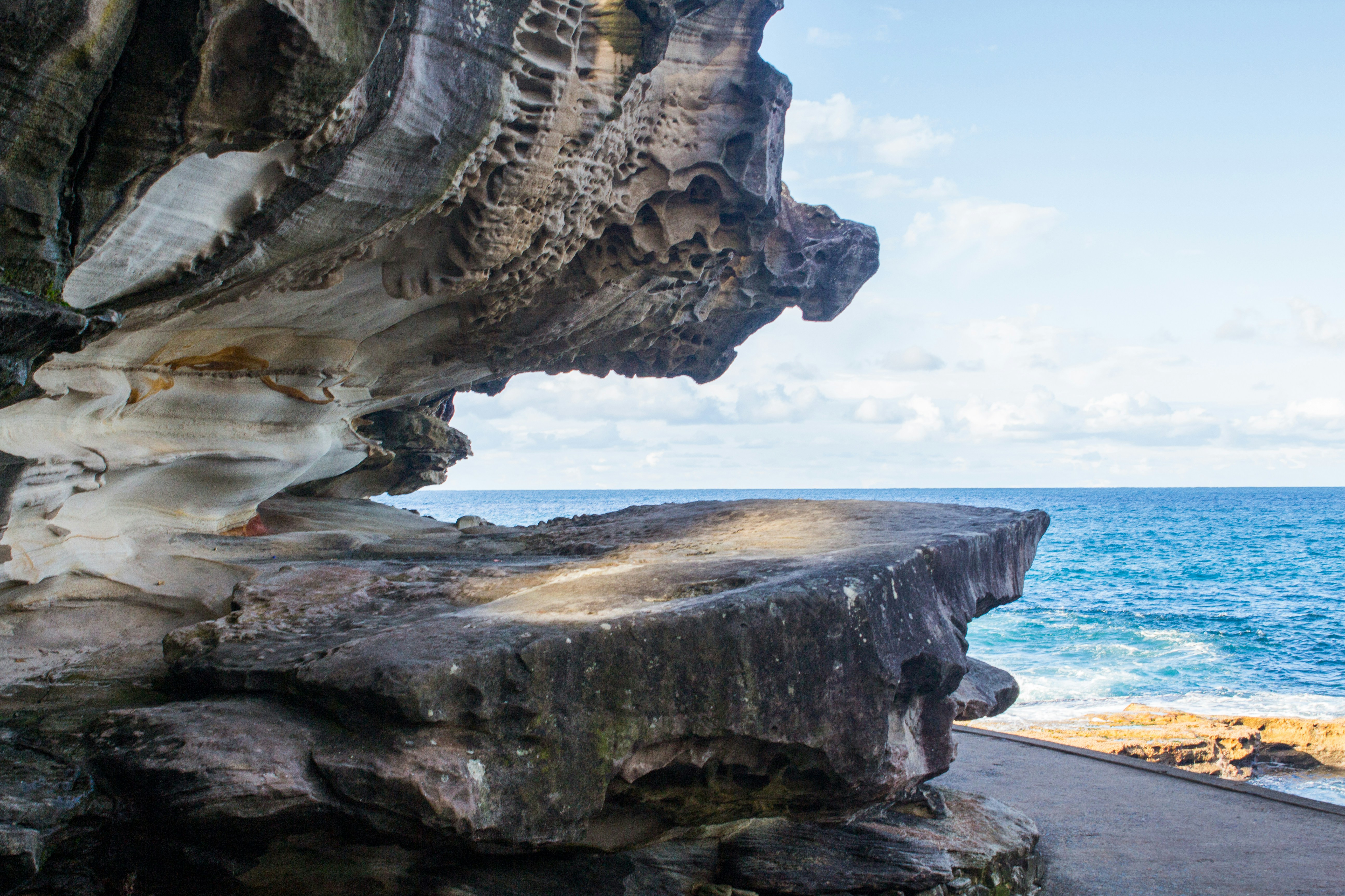 Stone Arch at the Shore: Textured Rock Framing a Blue Horizon