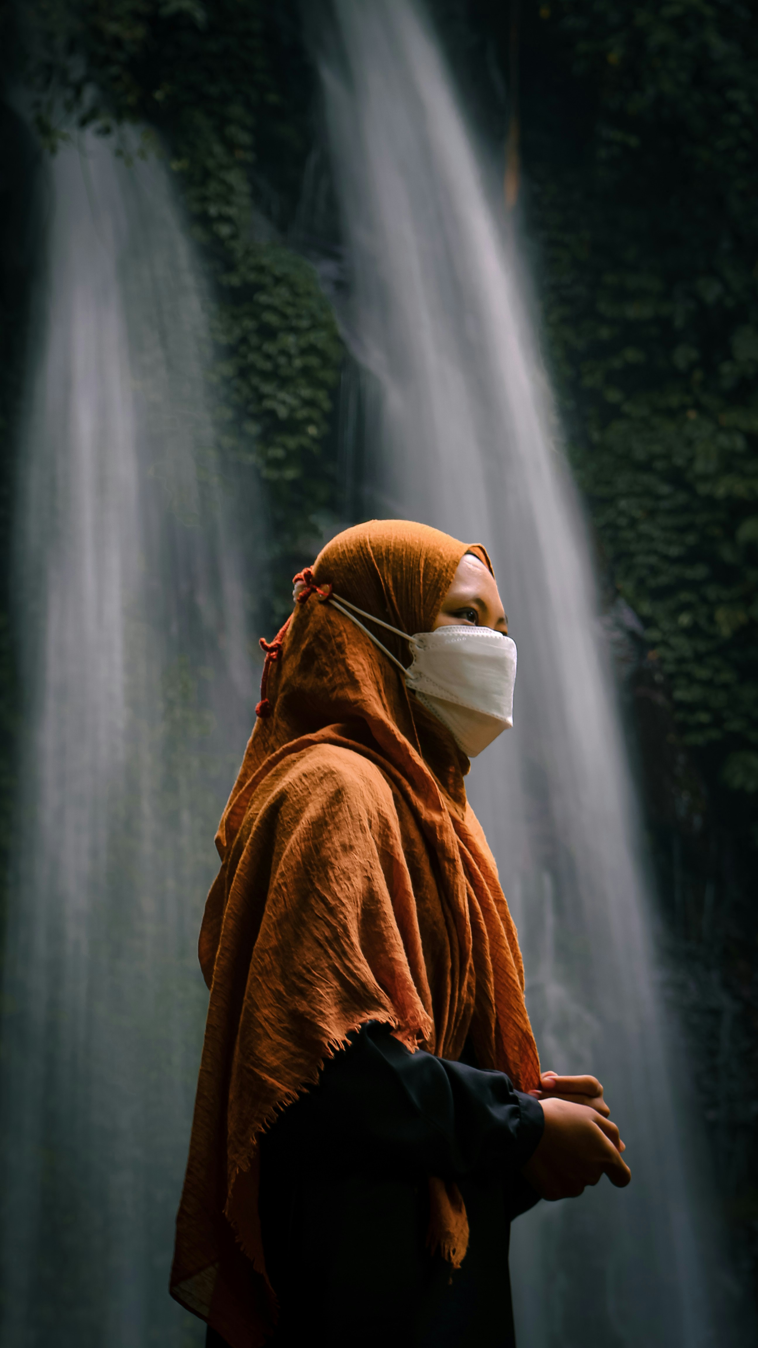 Masked silhouette against a cascading backdrop