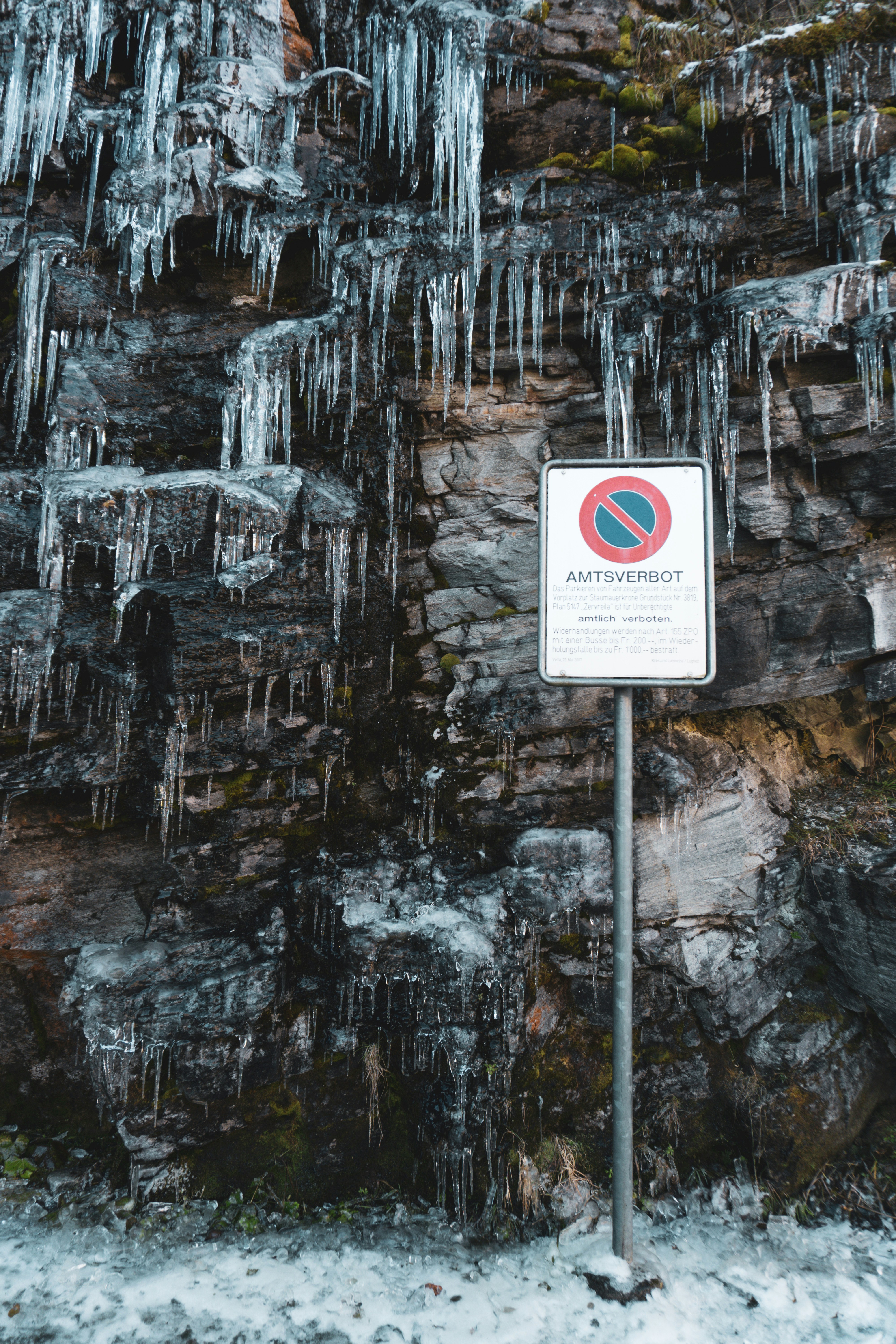 A sign on a pole in front of a wall of ice photo – Free Vals Image on ...