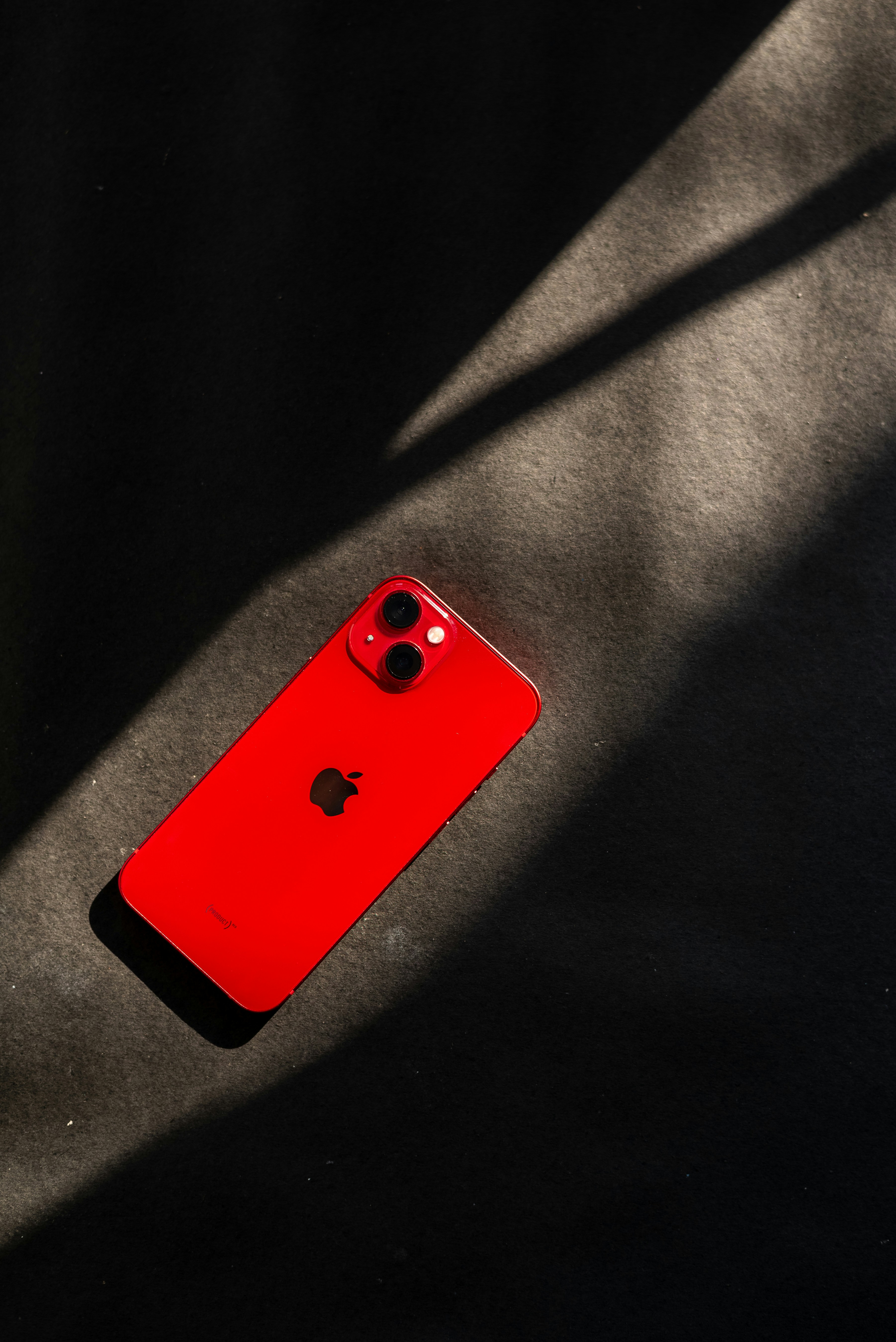 A red iphone sitting on top of a black surface photo – Free Phone Image ...