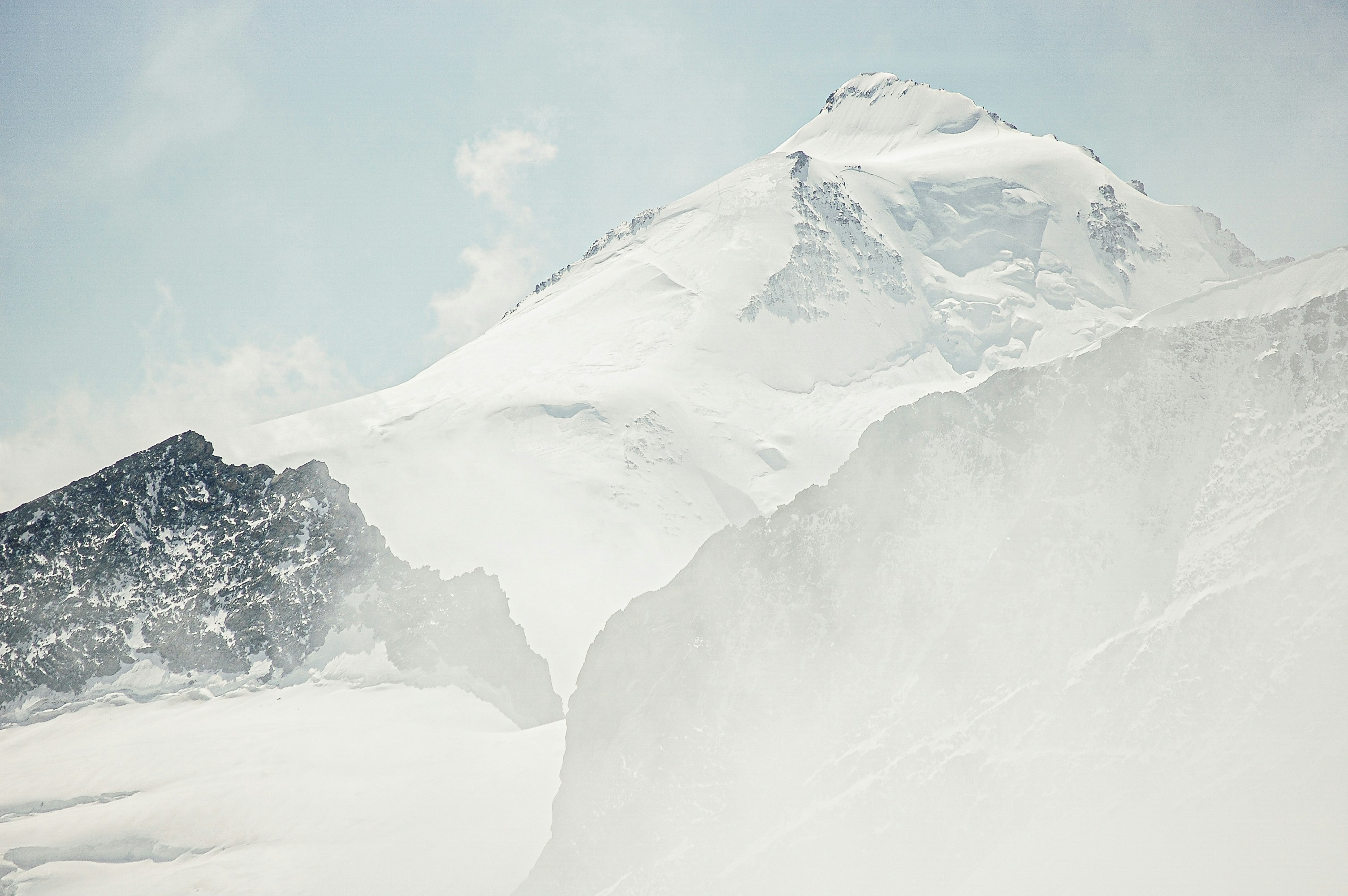 Snow-covered mountain peak partially obscured by mist, showcasing the rugged beauty of the alpine landscape.