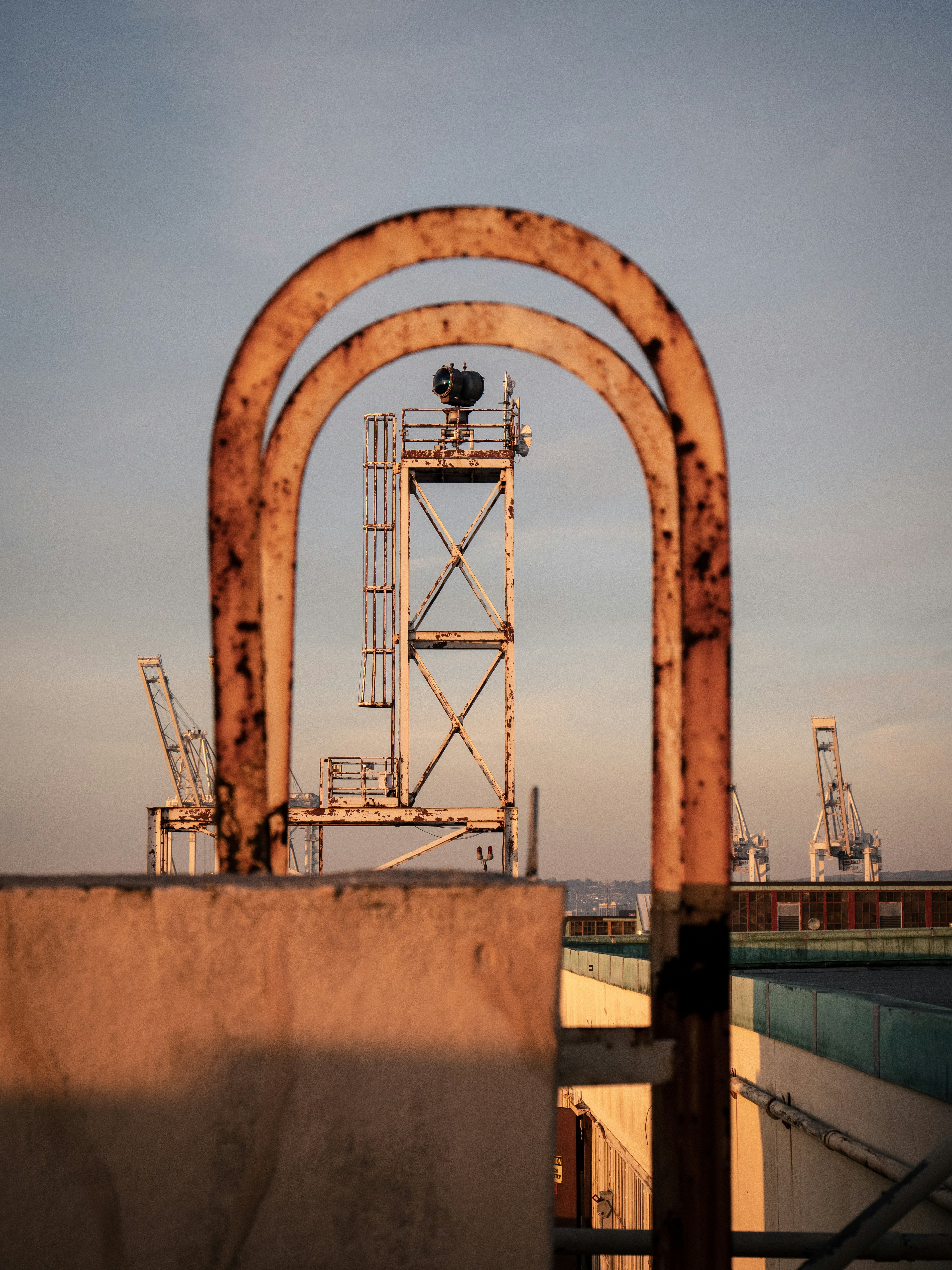 Rusted Arch Framing a Distant Crane: Sunset at the Rooftop Marina