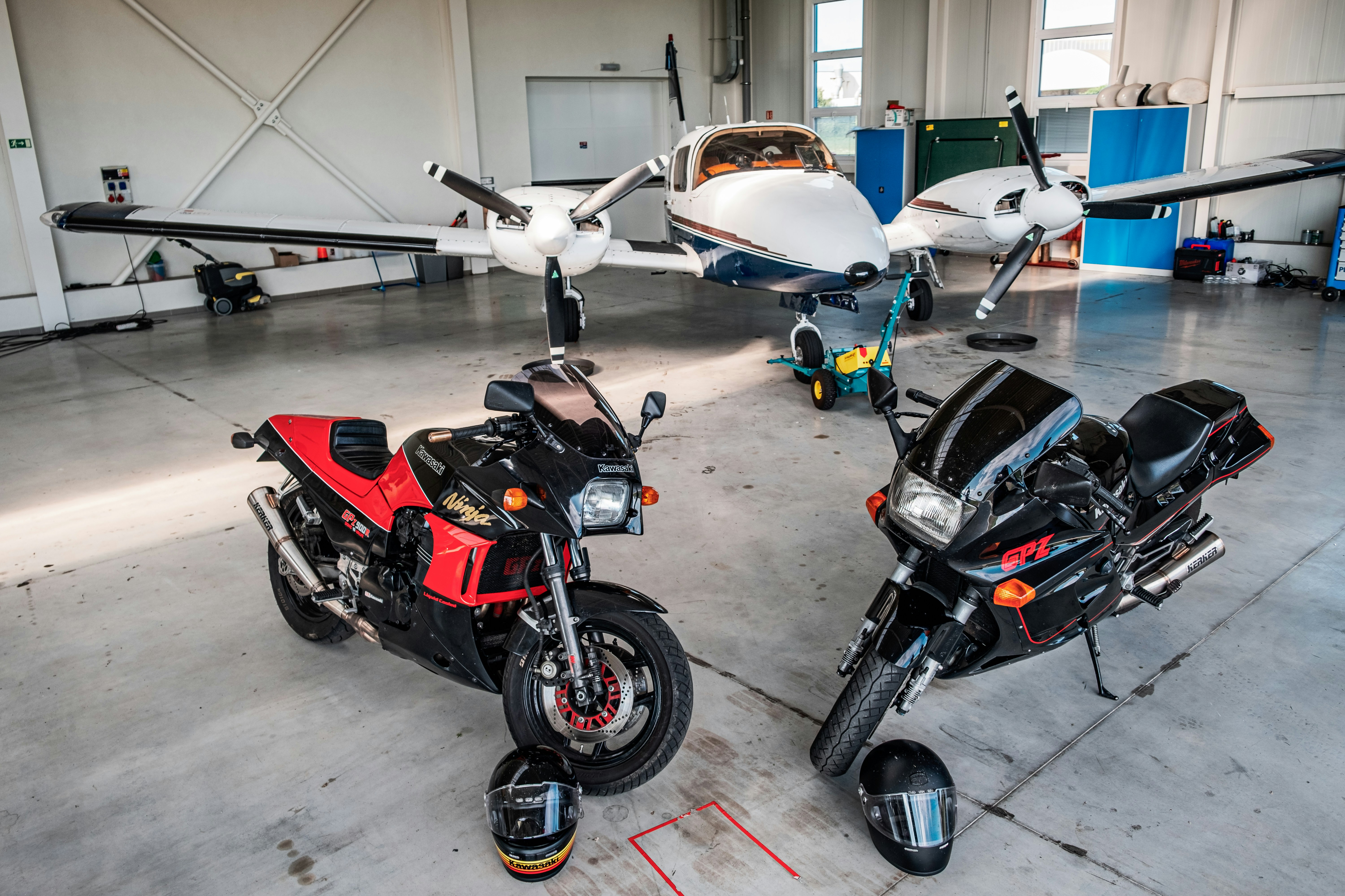 Two motorcycles parked in a garage next to an airplane photo – Free ...