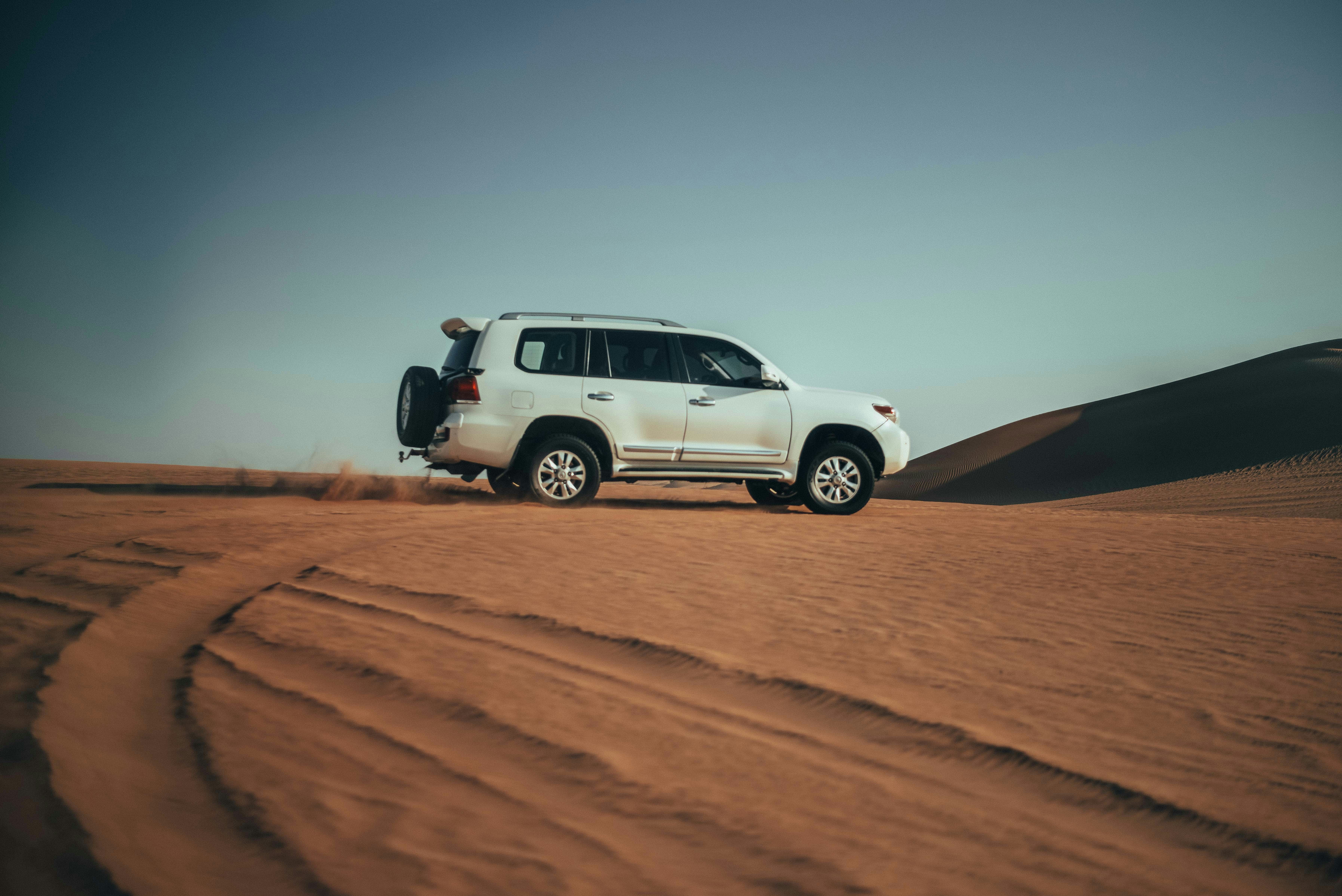 Un SUV blanc traversant le désert par une journée ensoleillée photo ...