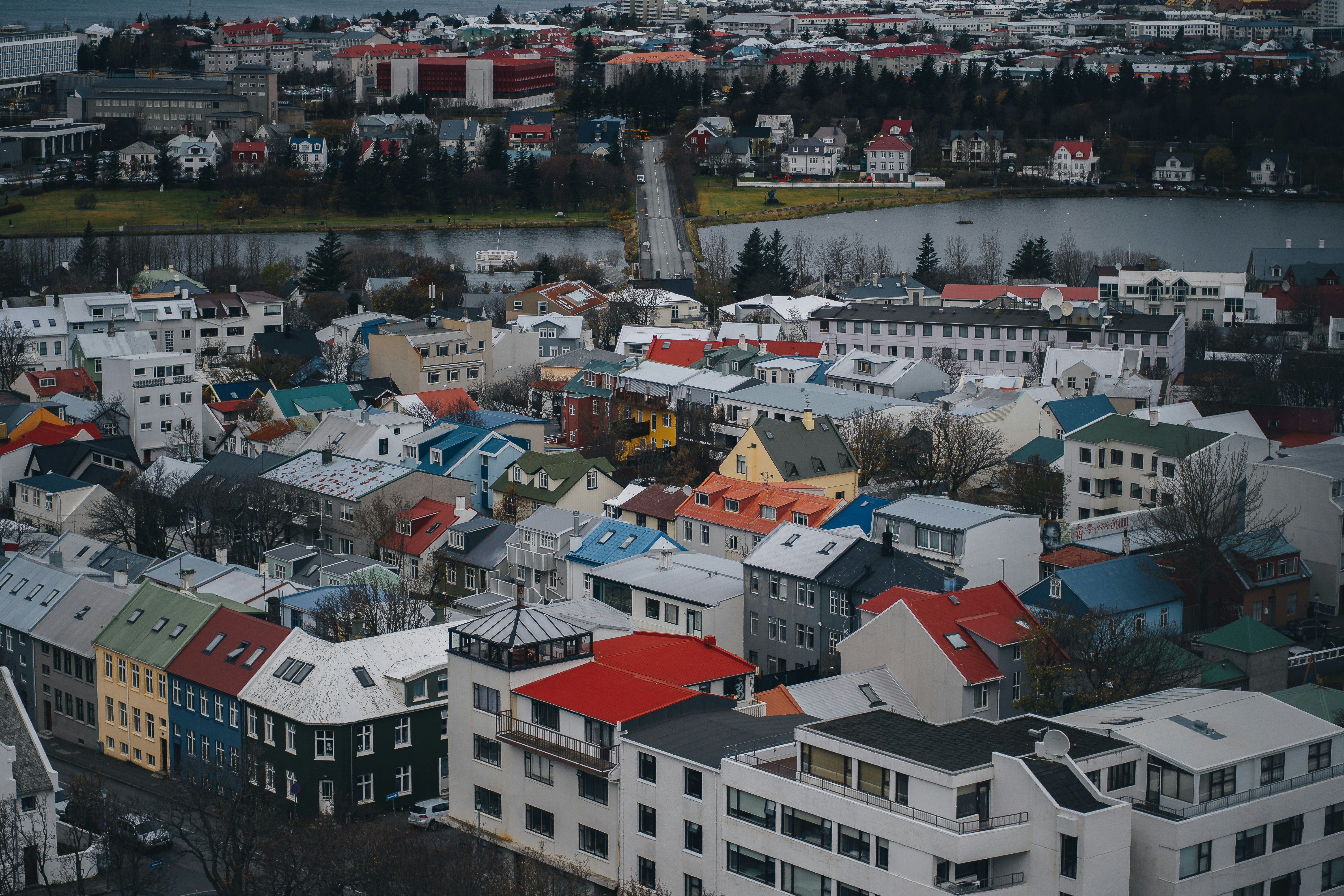 Aerial view of Reykjavik showcasing a vibrant mix of colorful rooftops amidst a serene landscape. The city’s unique architecture stands out against the calm waters nearby.