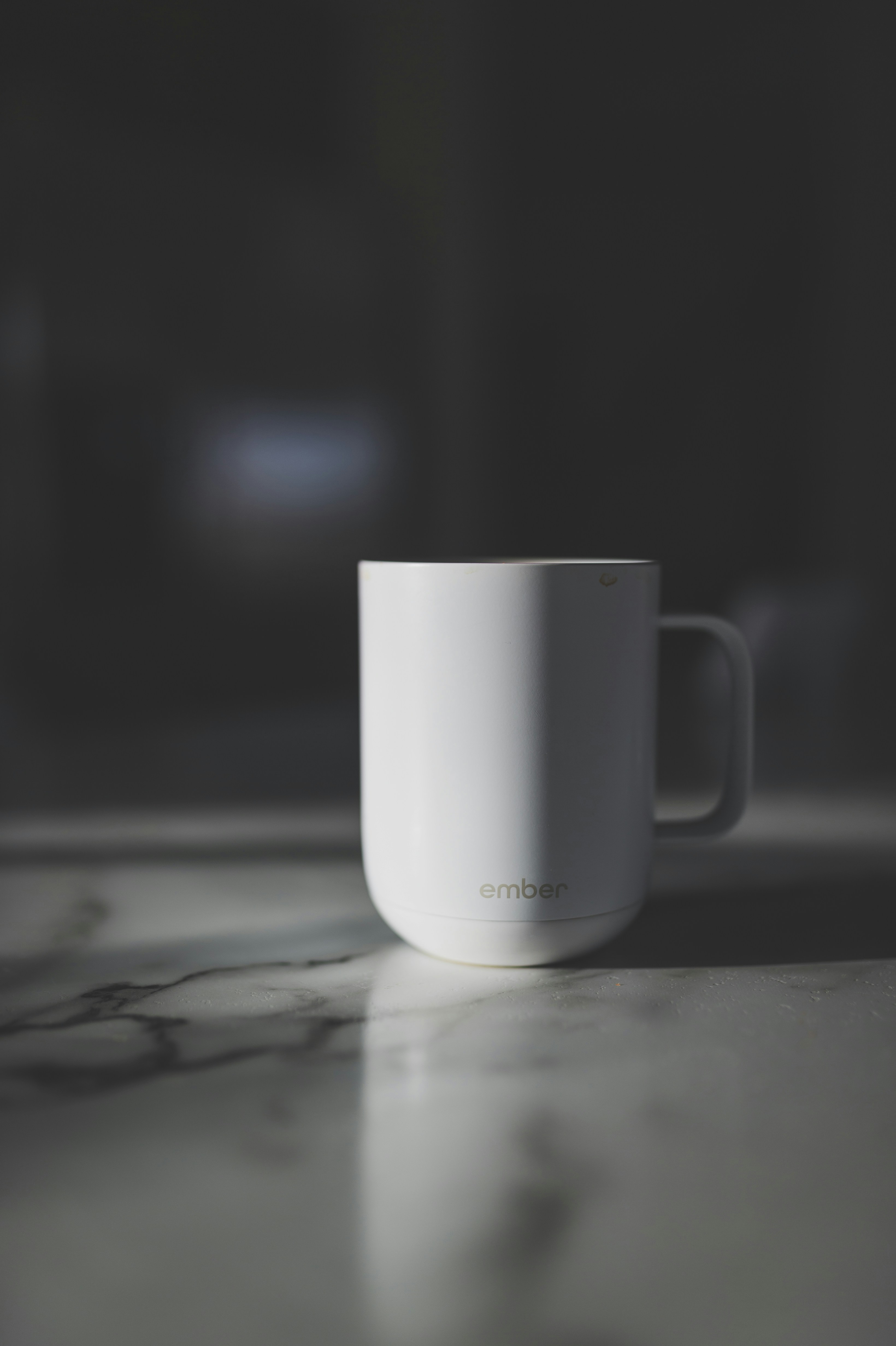 White Ember mug resting on a marble surface, illuminated by soft natural light creating a serene atmosphere.