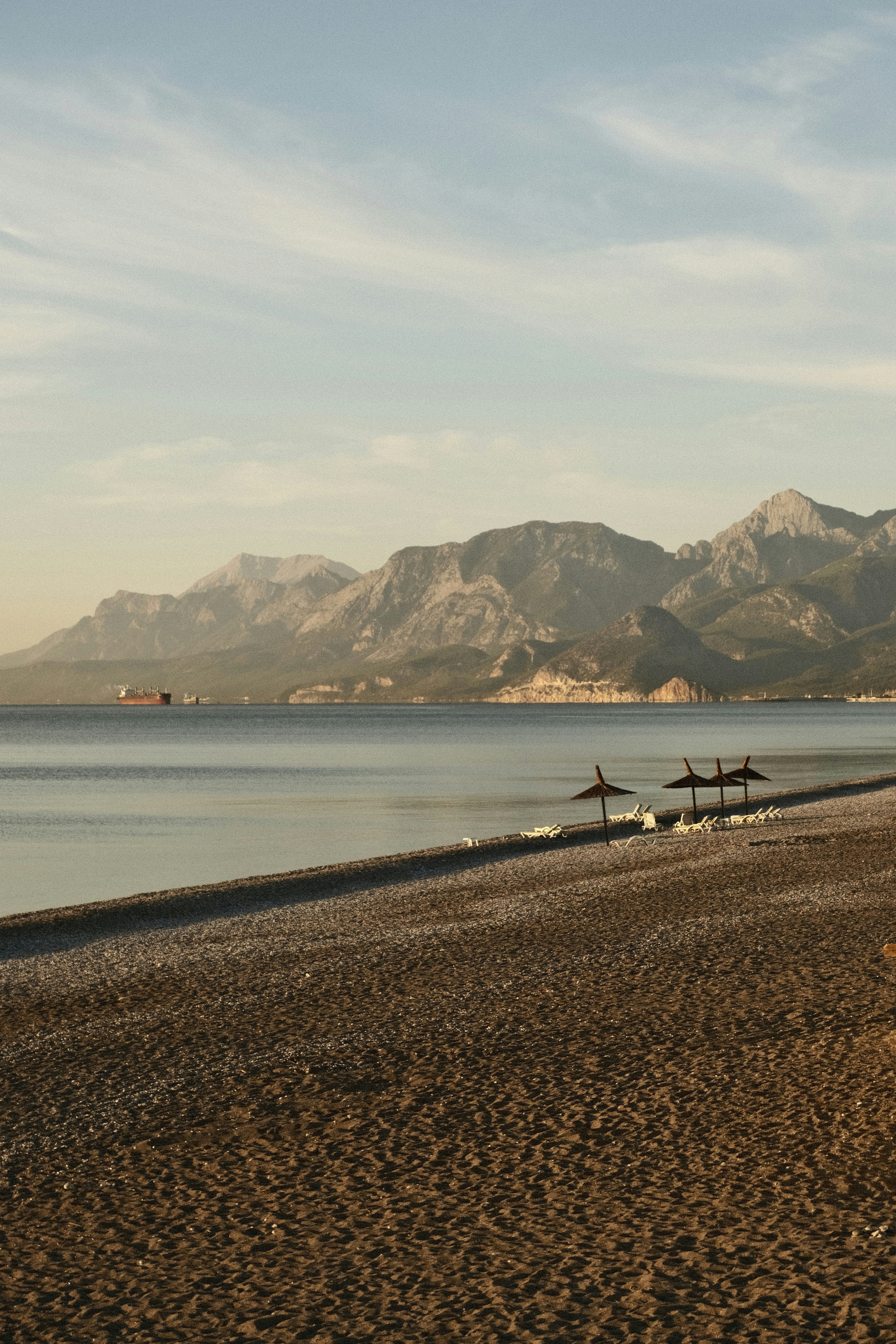 a sandy beach with mountains in the background