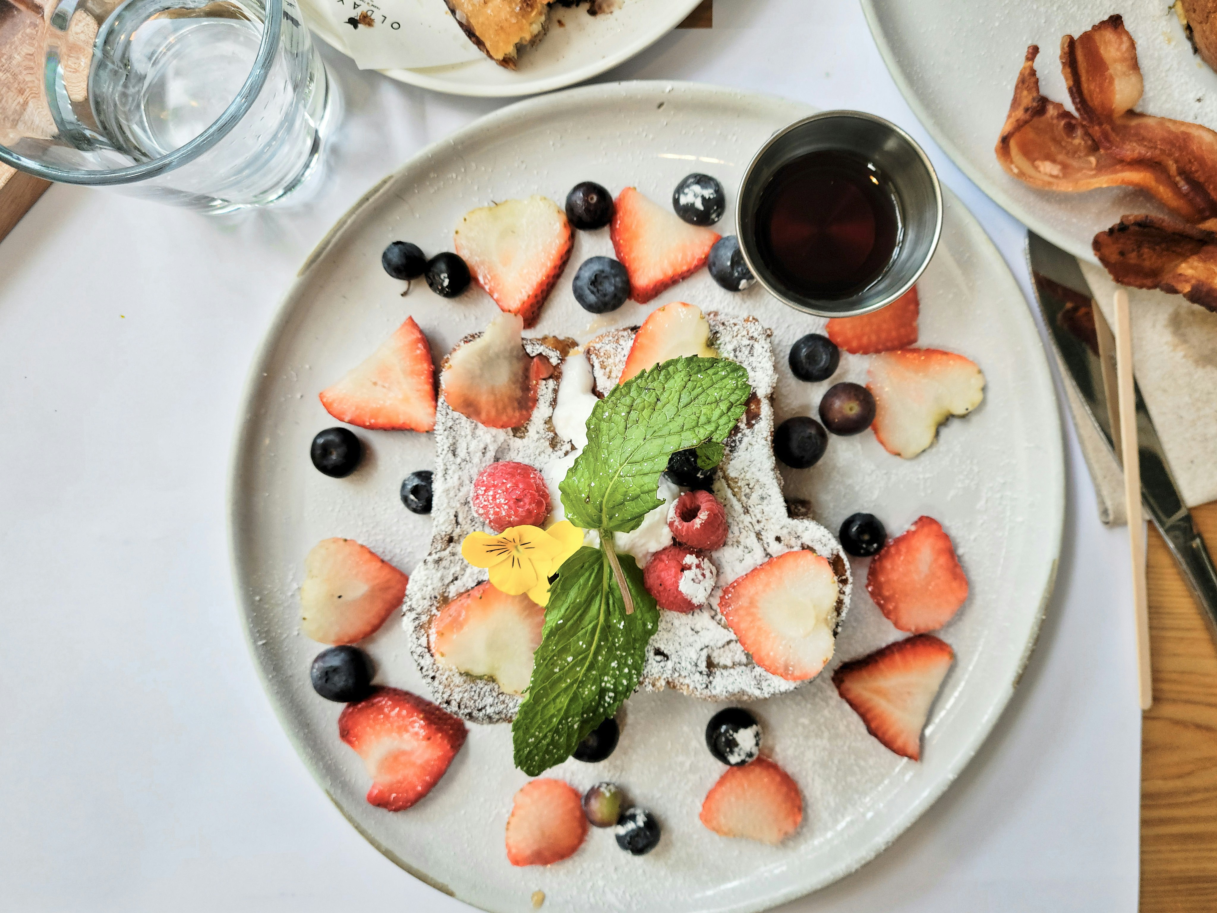 a white plate topped with fruit next to a cup of coffee