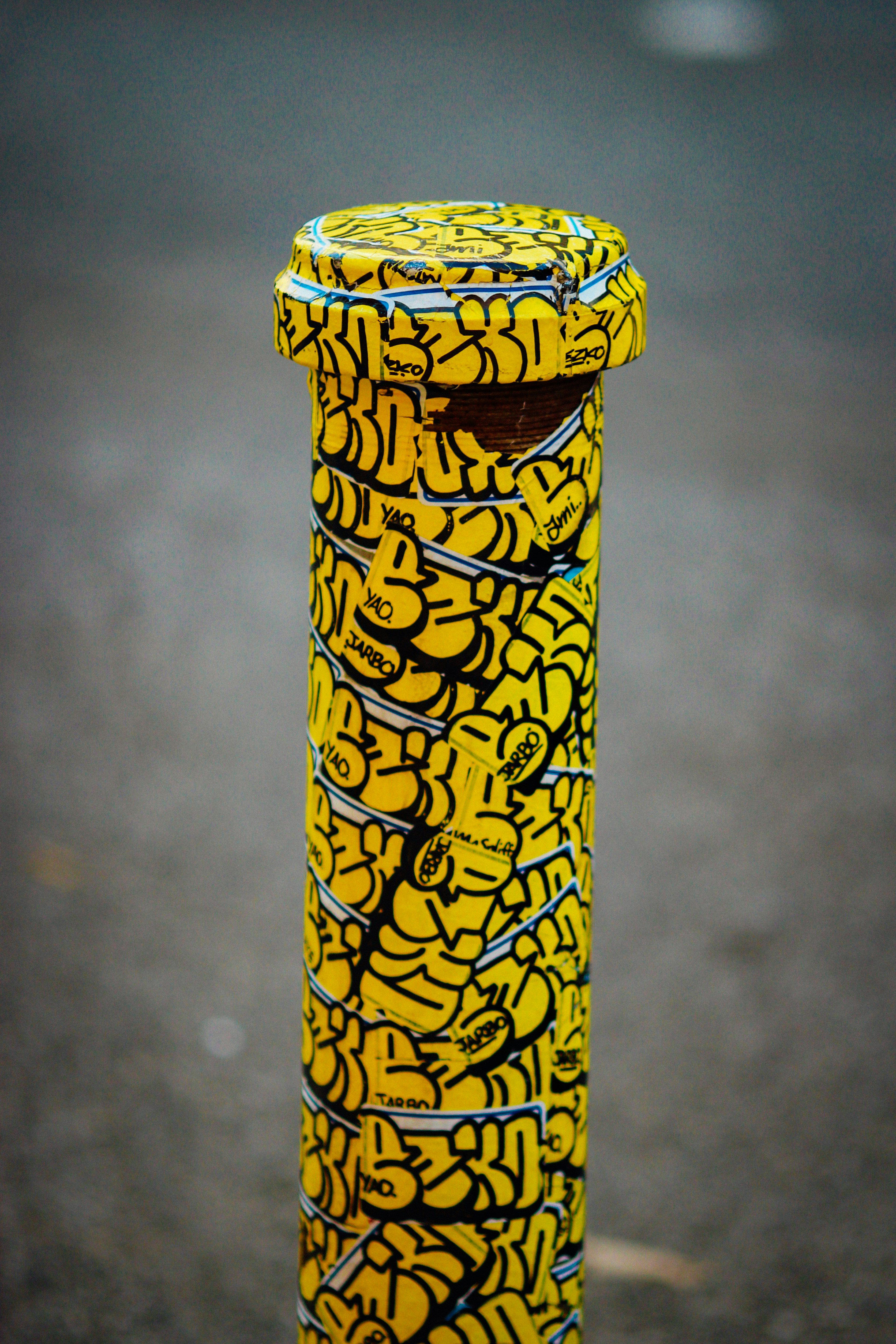 Graffiti-Wrapped Bollard: Neon Yellow on a Quiet Street