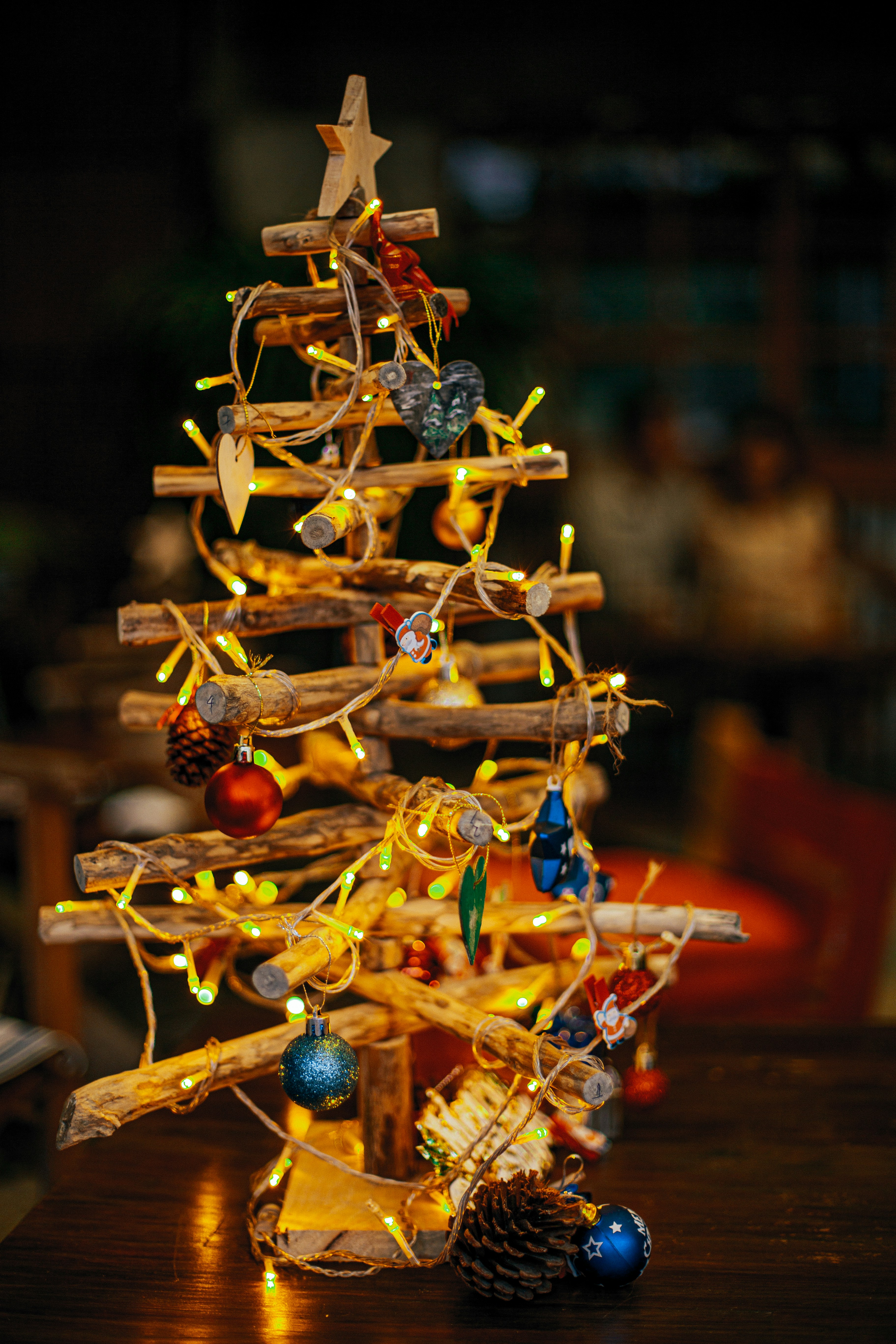 A charming wooden Christmas tree adorned with colorful ornaments and twinkling lights, set against a cozy indoor backdrop.