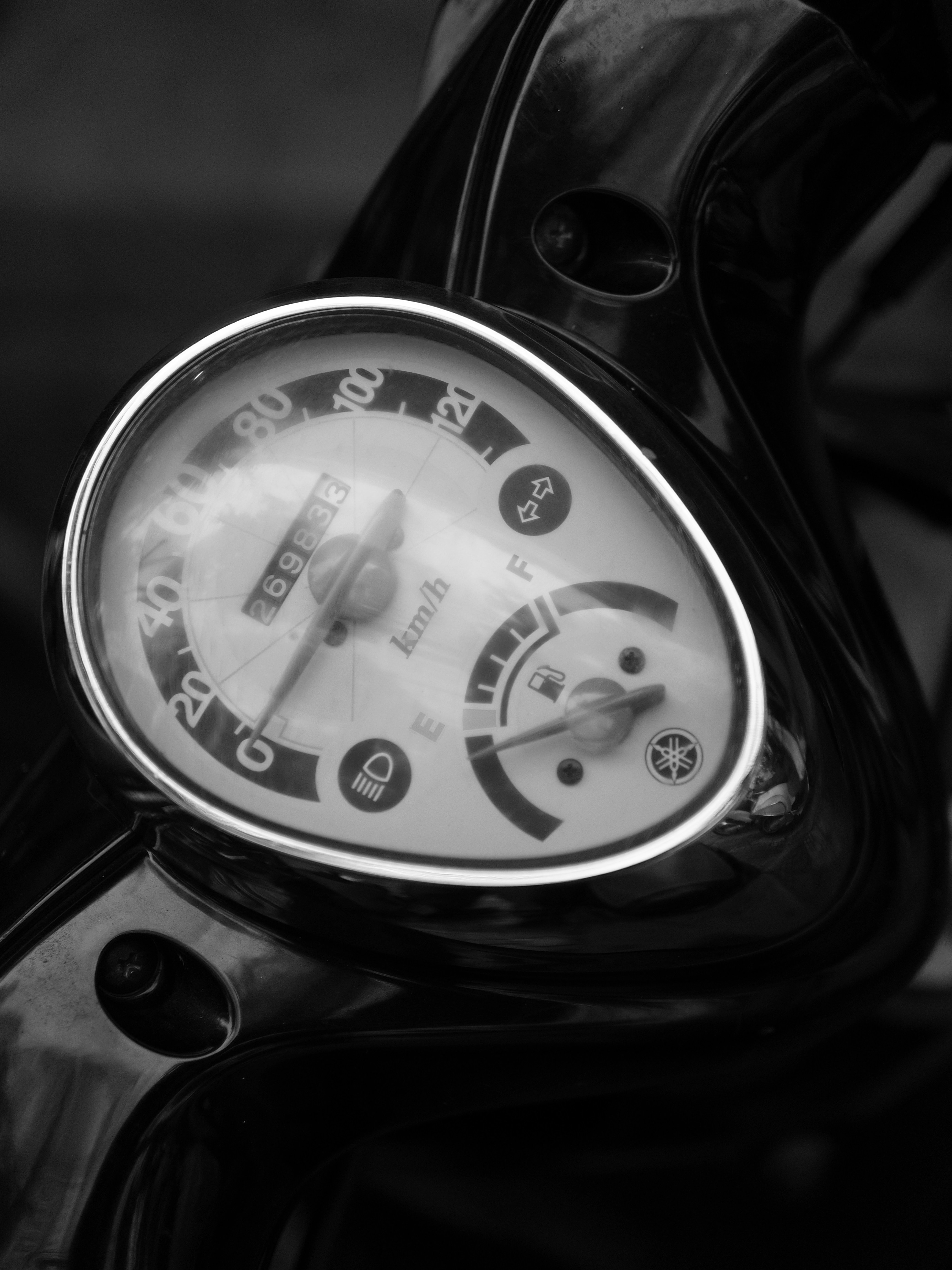 Close-up of a vintage speedometer displaying speed and fuel levels in a monochromatic setting.