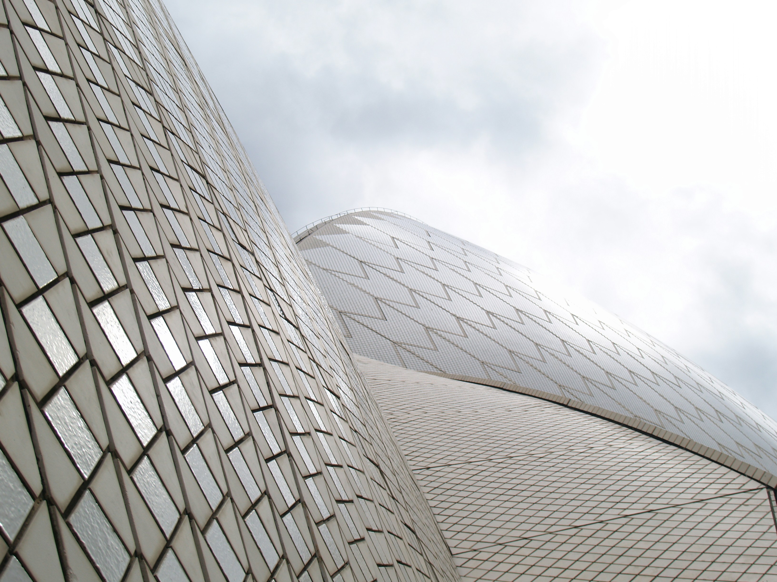 Abstract view of the Sydney Opera House's shell-like structure, showcasing its unique geometric patterns and reflective surfaces.