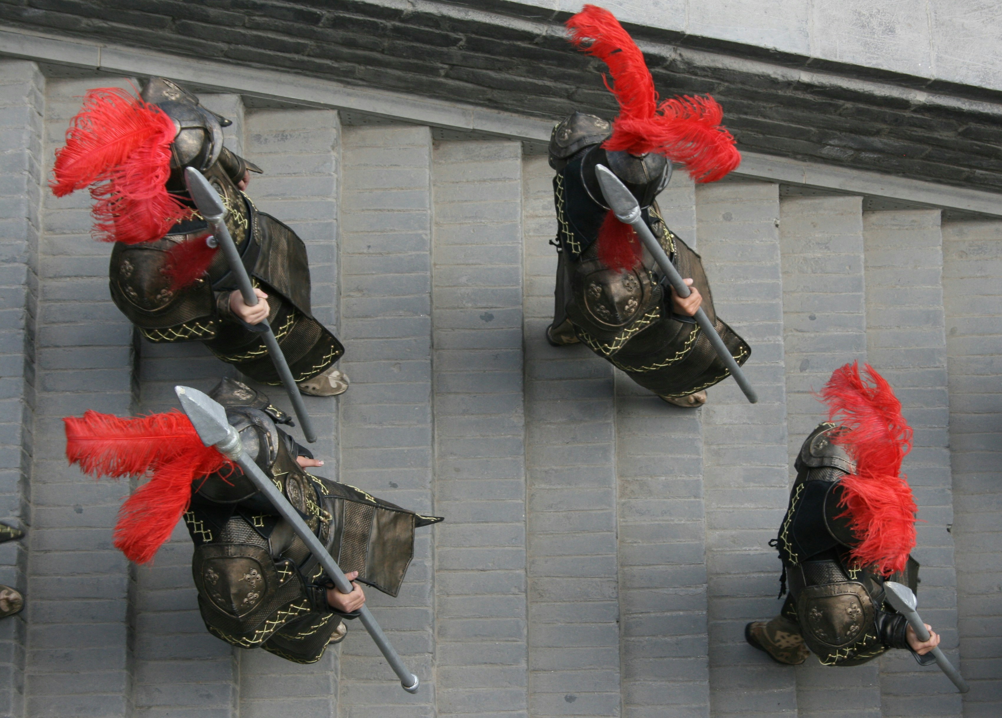 Medieval-clad figures with red plumes ascending stone stairs.