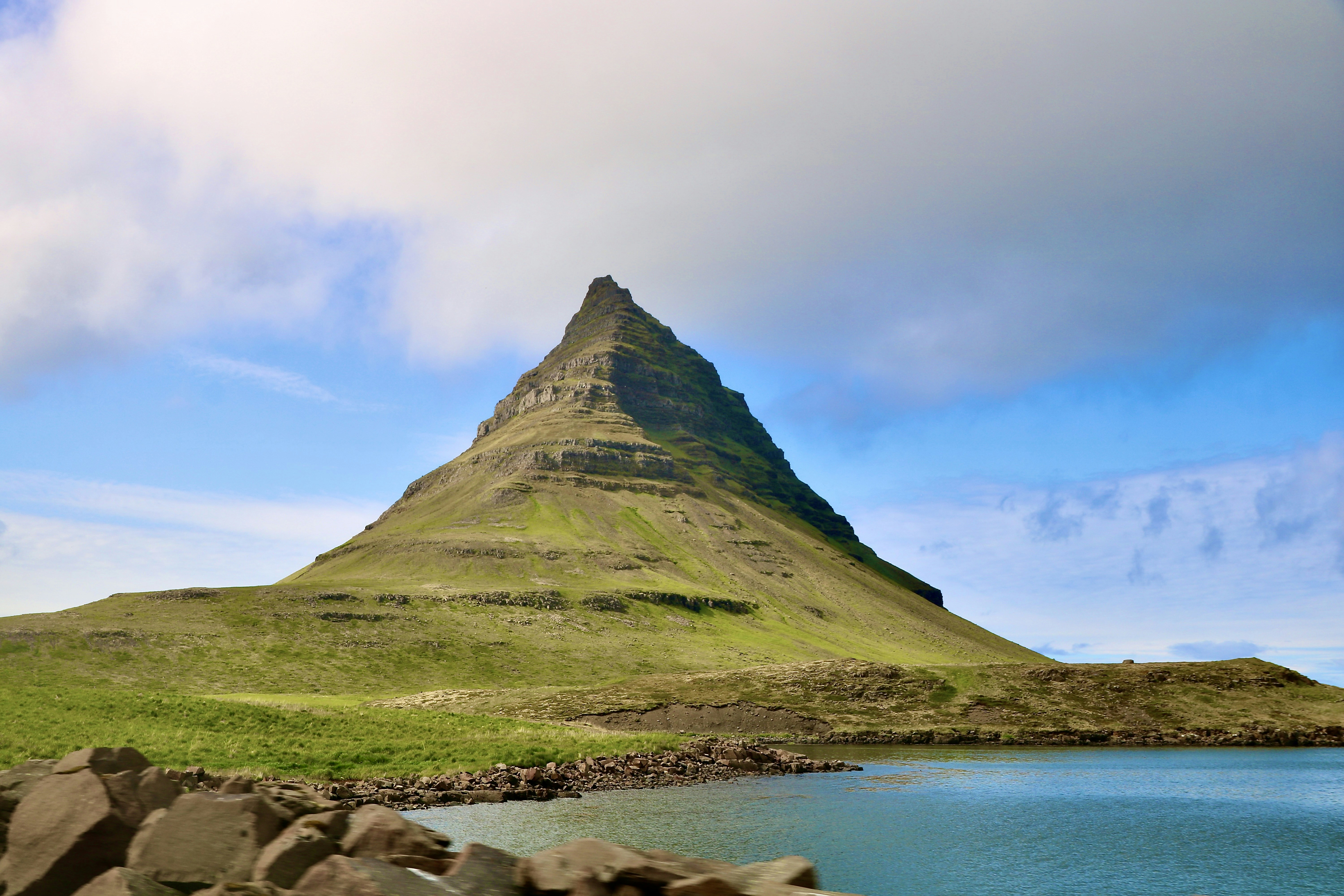 A very tall mountain sitting above a body of water photo – Free Nature ...