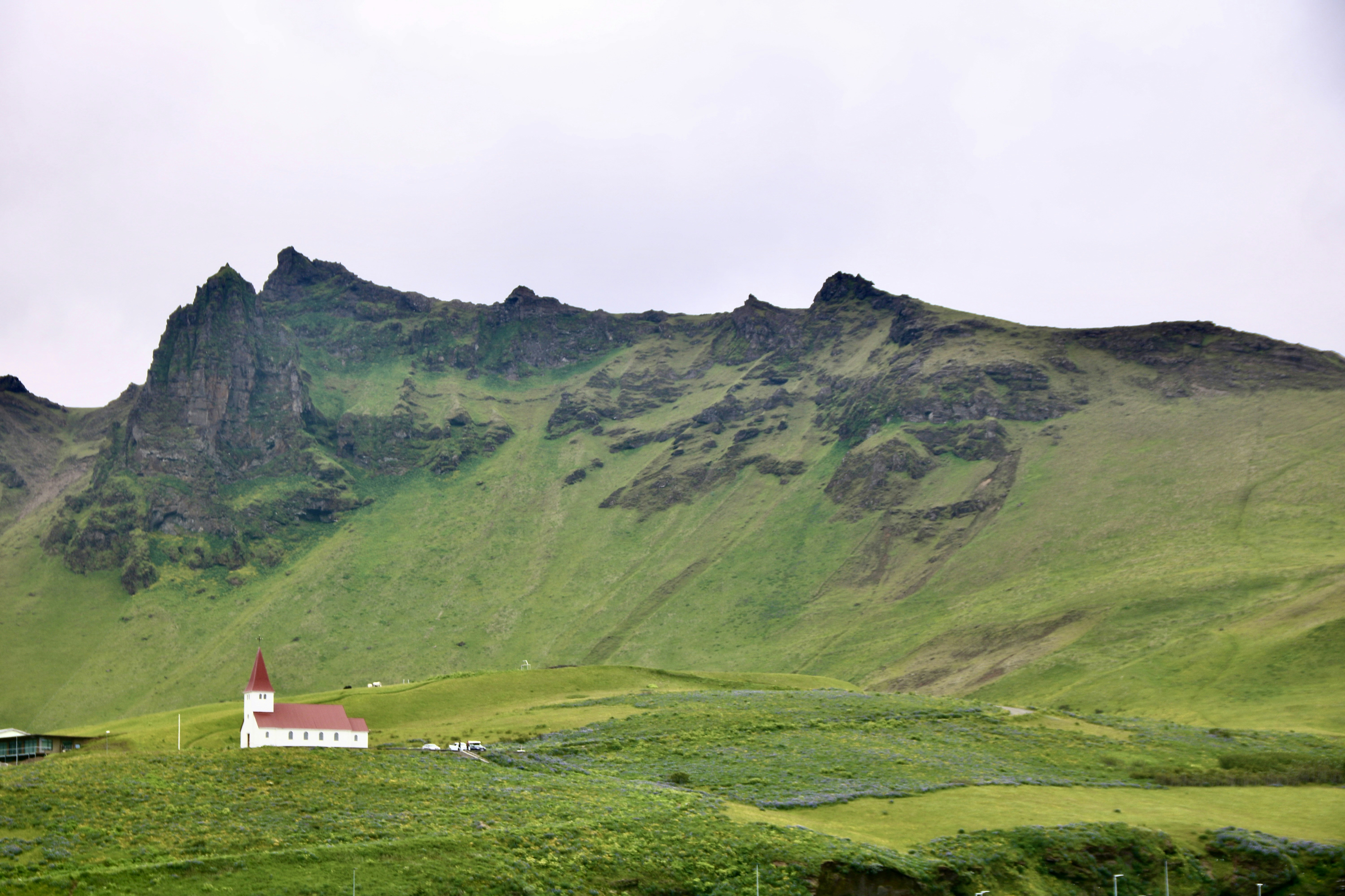 A small church on a grassy hill with a mountain in the background photo ...