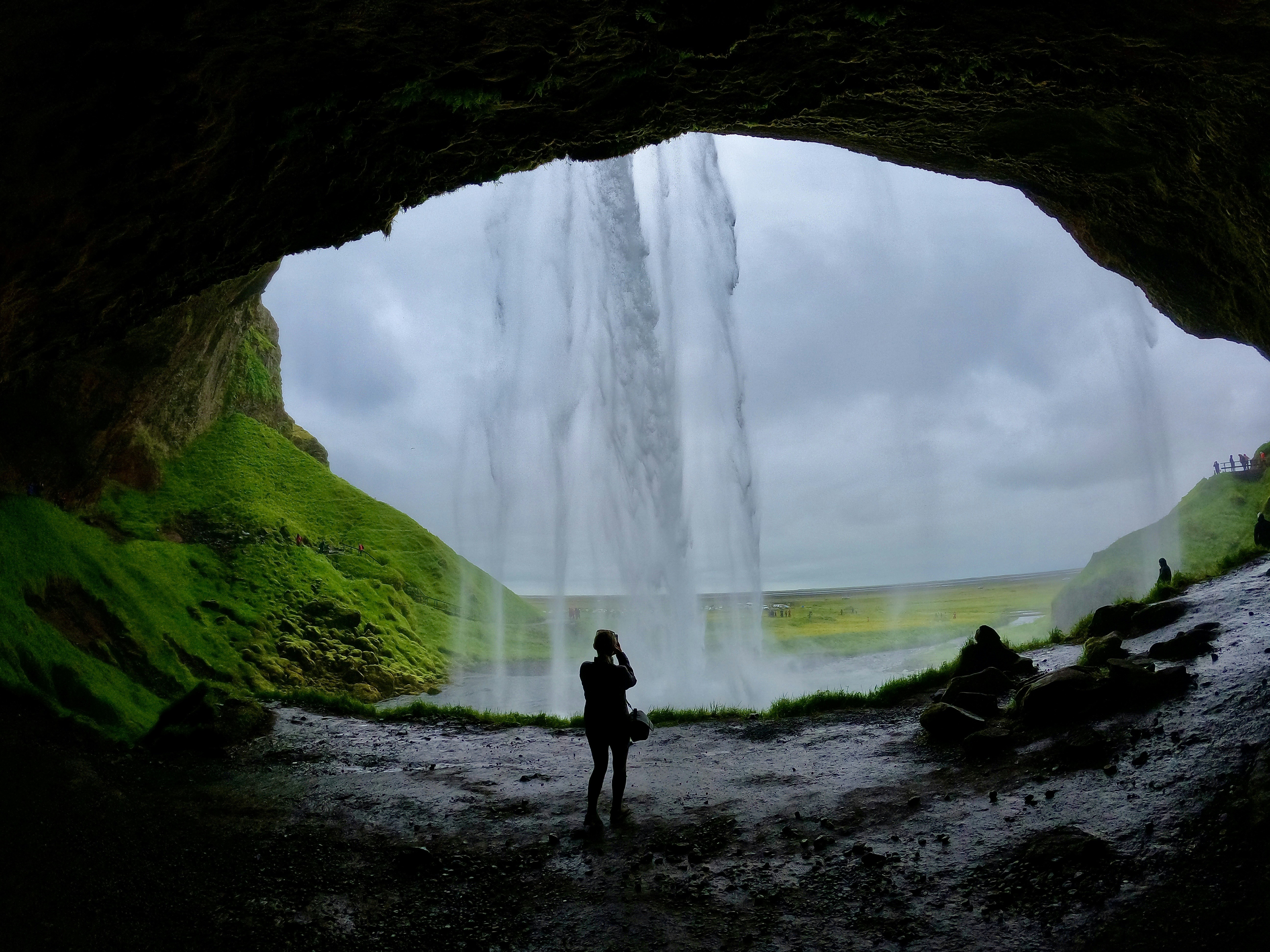 Une personne debout dans une grotte avec une cascade en arrière-plan ...